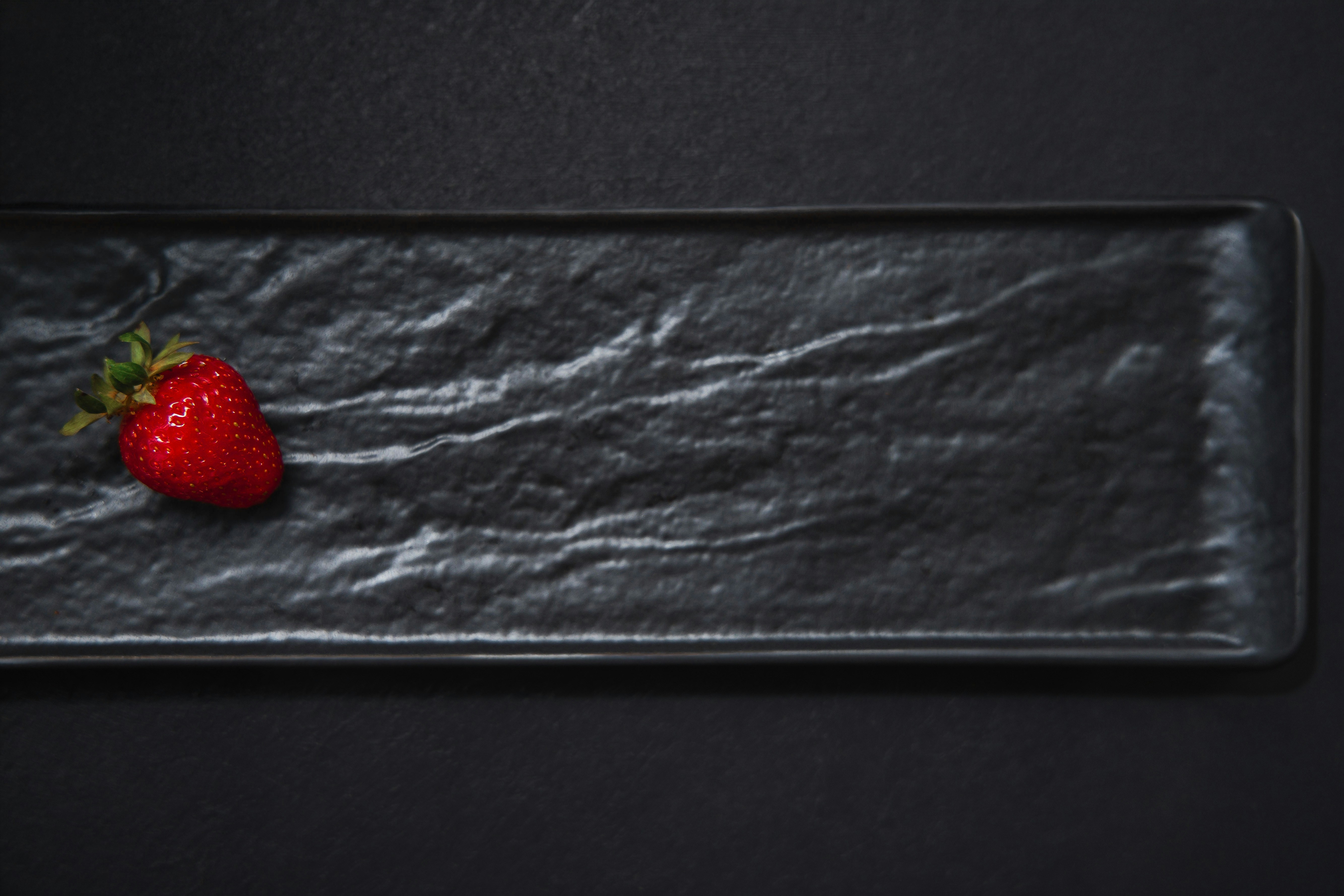 Single strawberry on a dark chocolate tray