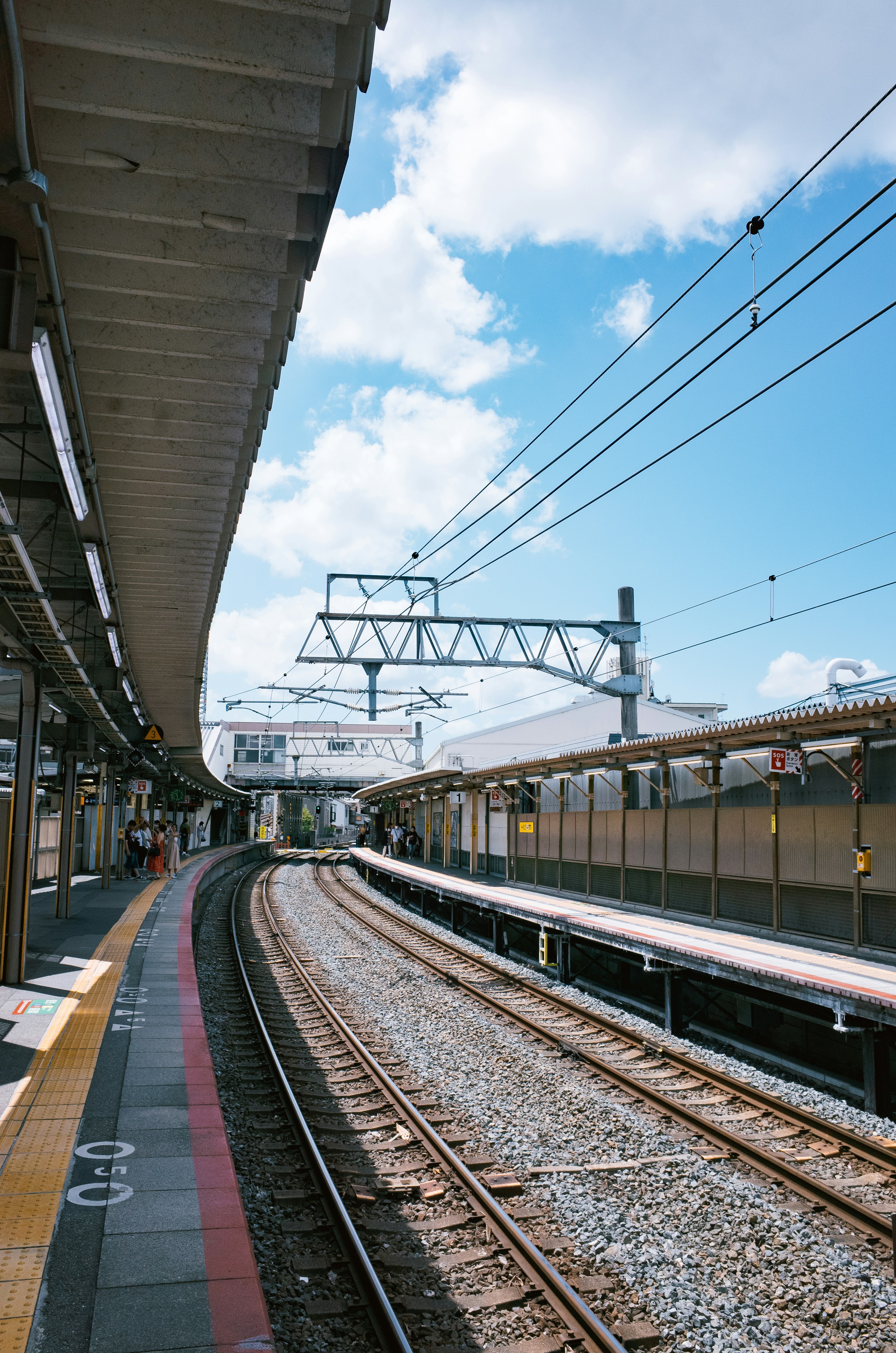 Empty train tracks and station platform under a blue sky.