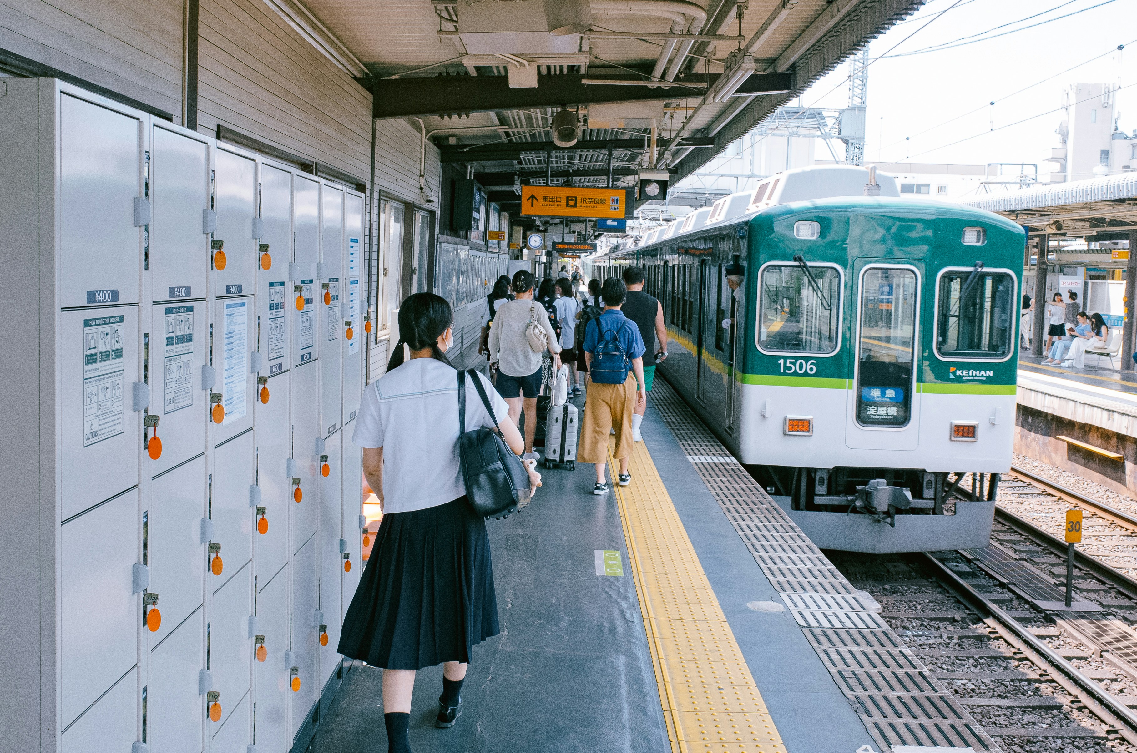 Platform Pulse: Commuters Converge as a Green-White Train Arrives