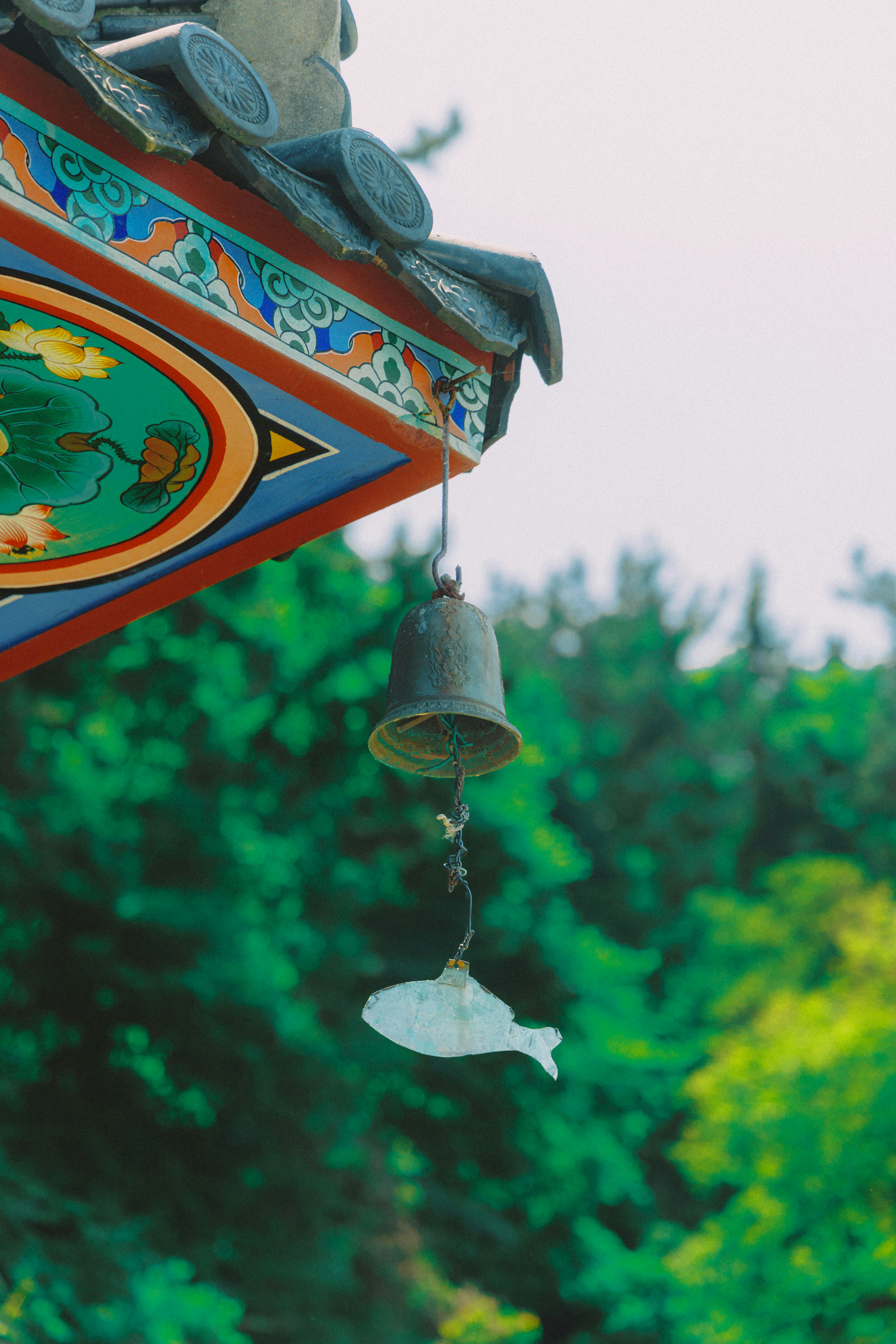 Colorful temple roof with a hanging bell and fish.