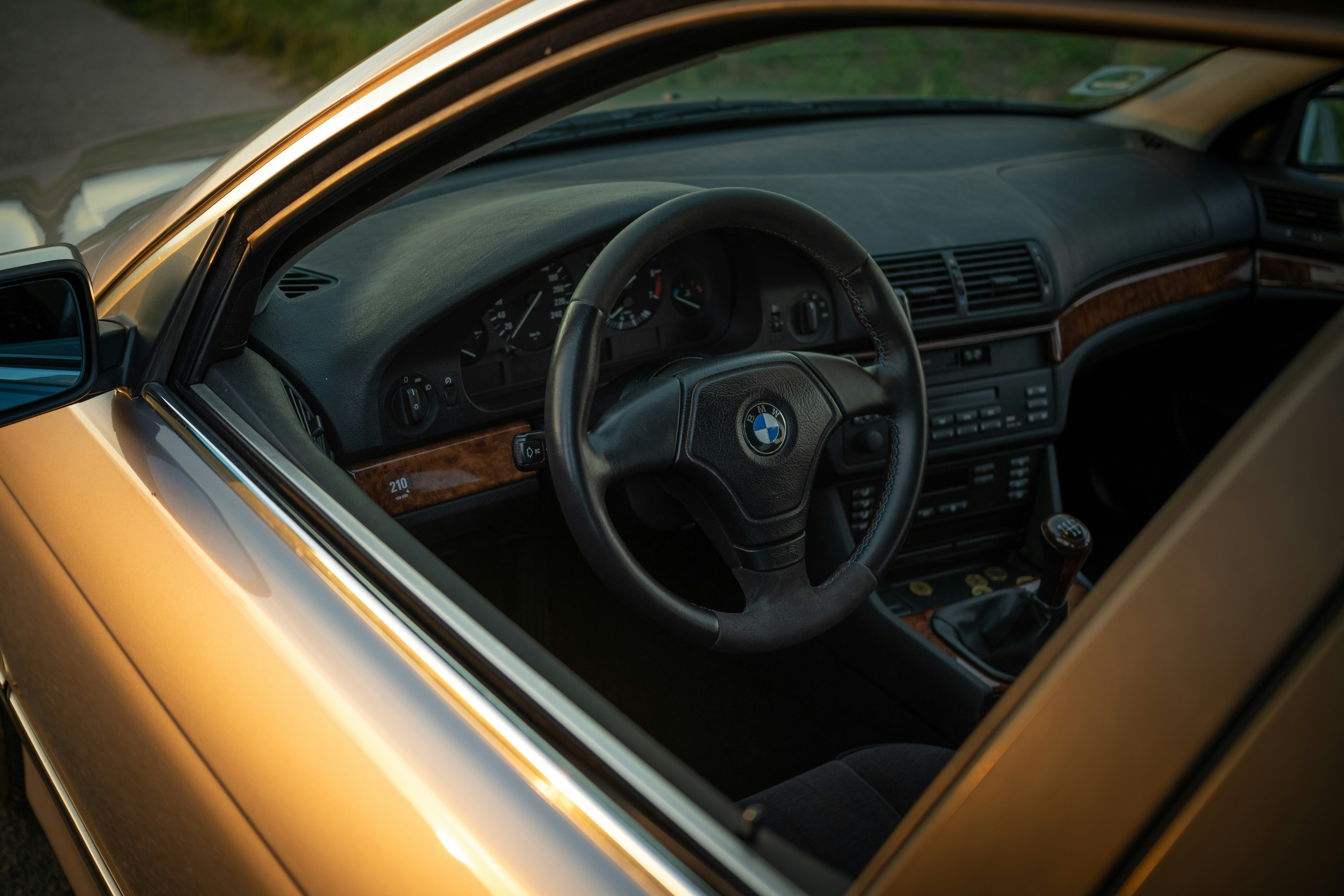 Sunlit Cockpit: A Classic BMW Steering Wheel and Wooden Dash