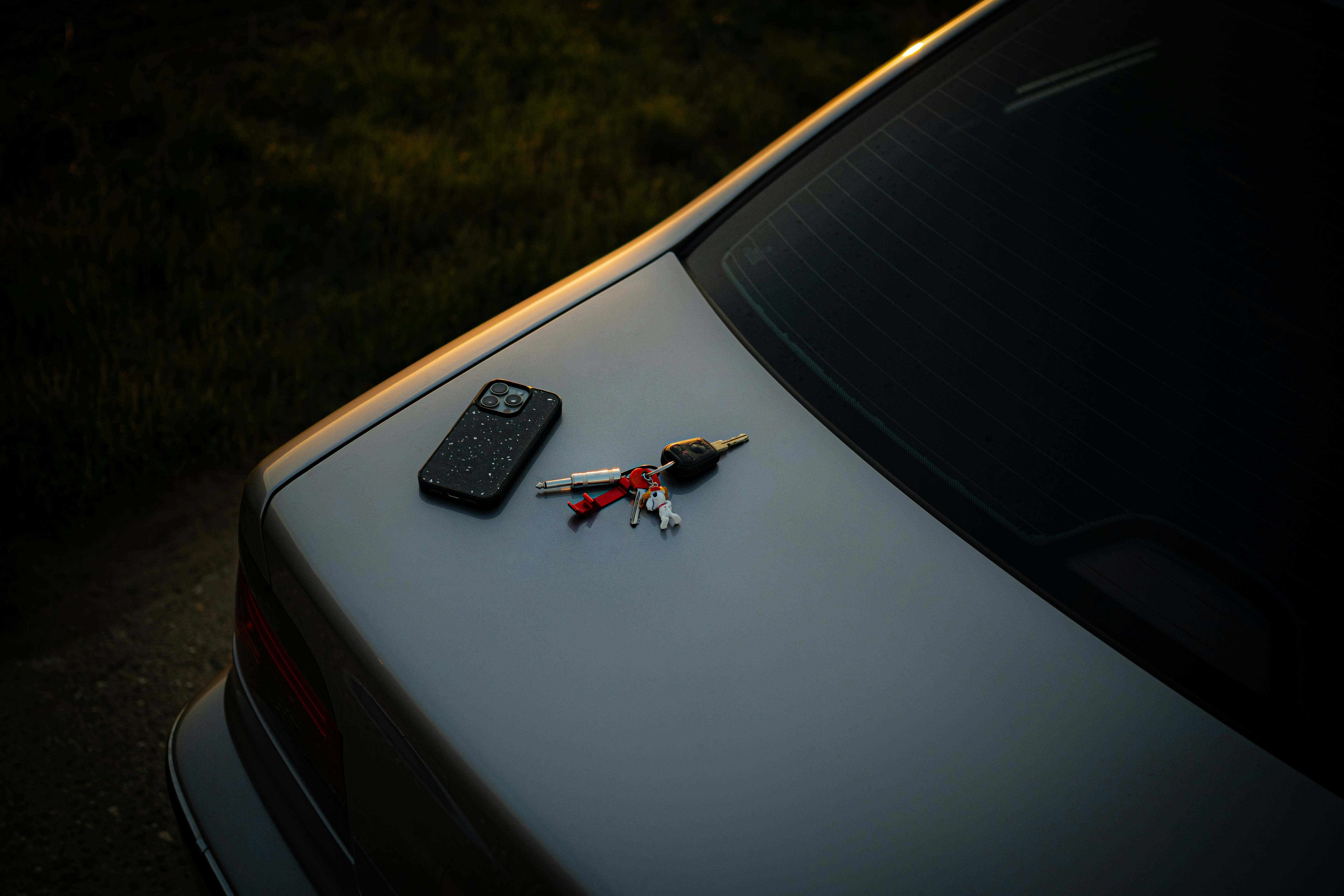 Keys and remote on a car’s metallic trunk at dusk