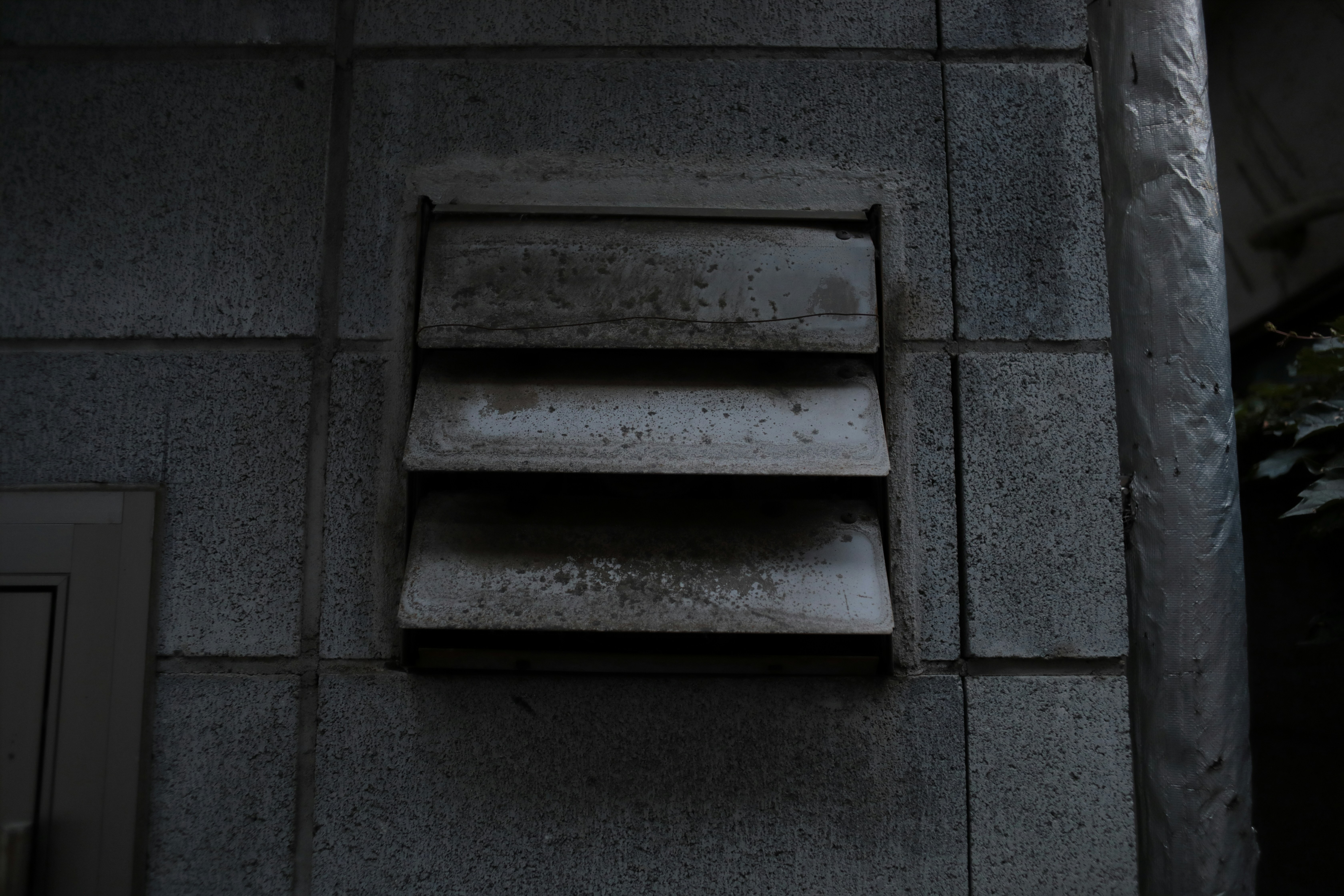 Weathered vent slats on a concrete facade