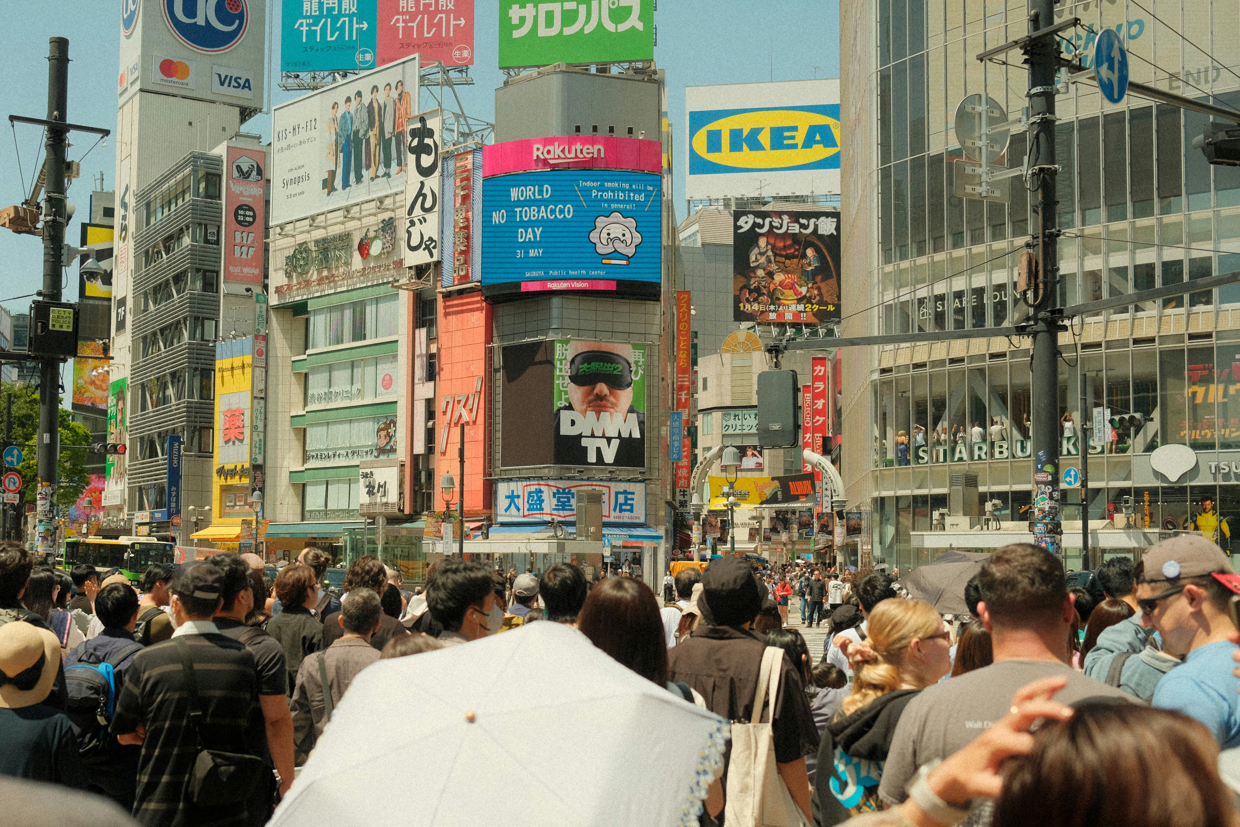 Crowded city street with tall buildings and advertising billboards.