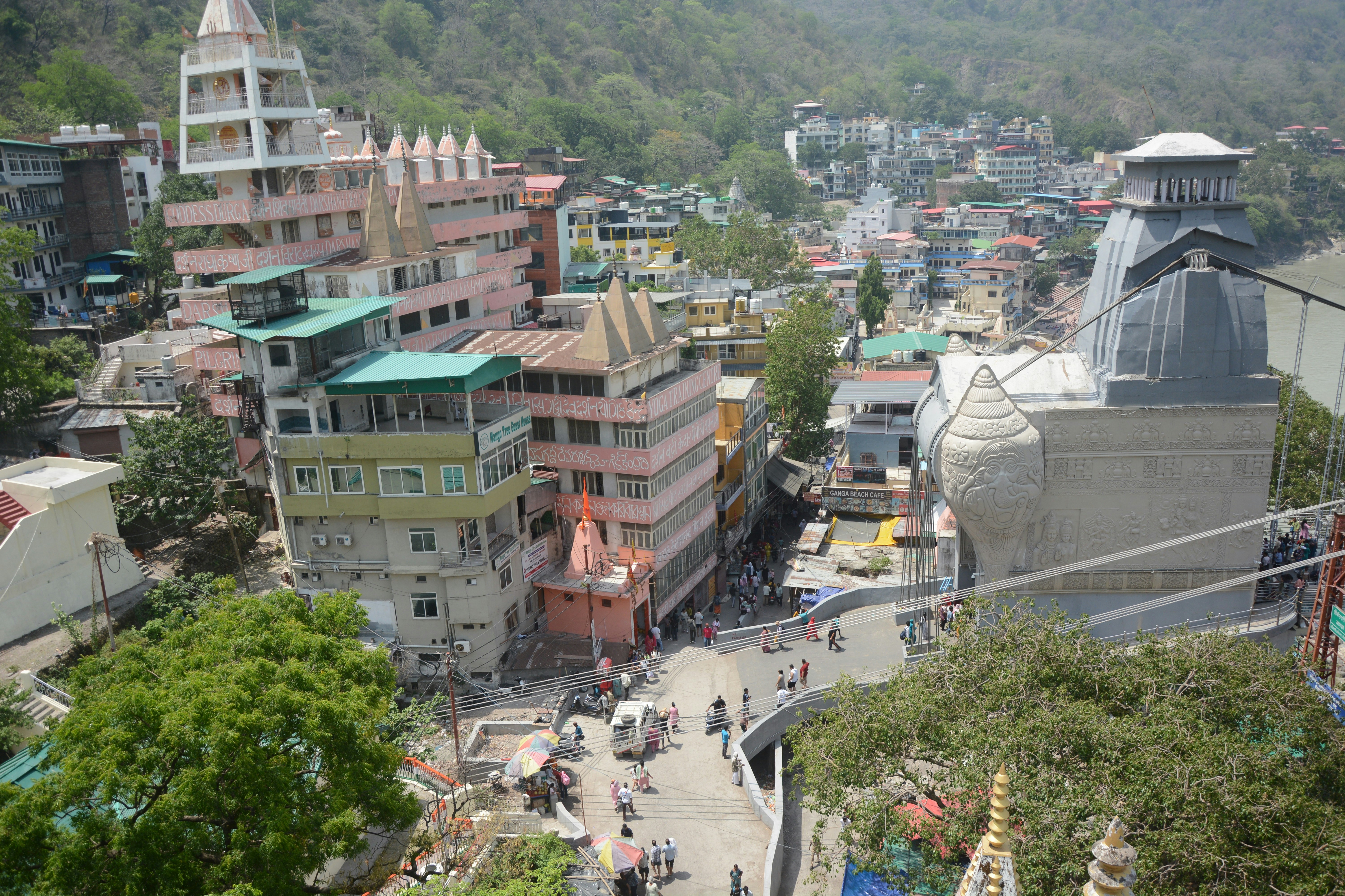 Outdoor street scene around a hillside temple complex with colorful multi-story buildings and people strolling along steps.