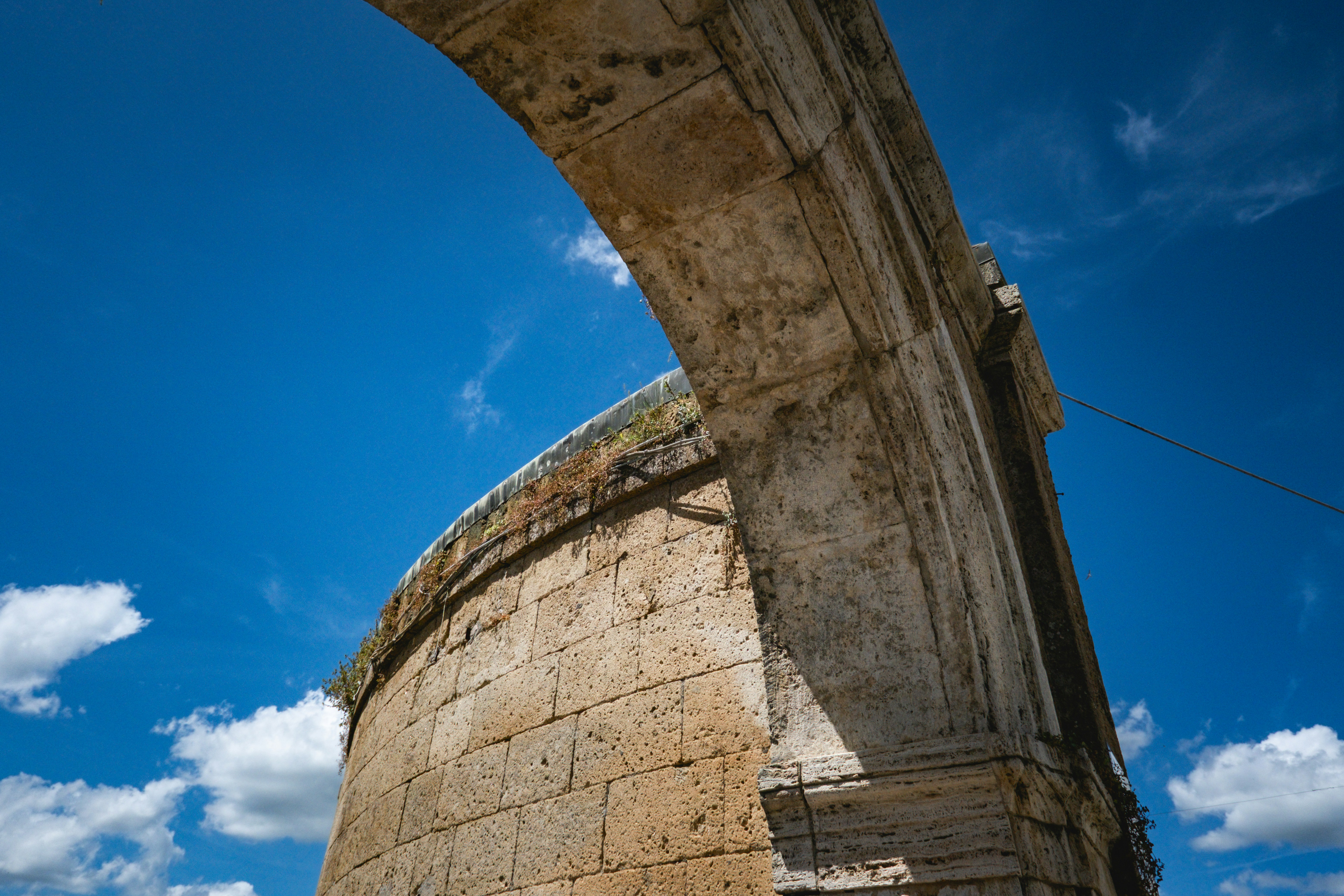 Arch Over Blue: A Curved Stone Cairn Reaches Toward a Sky-Blue Span