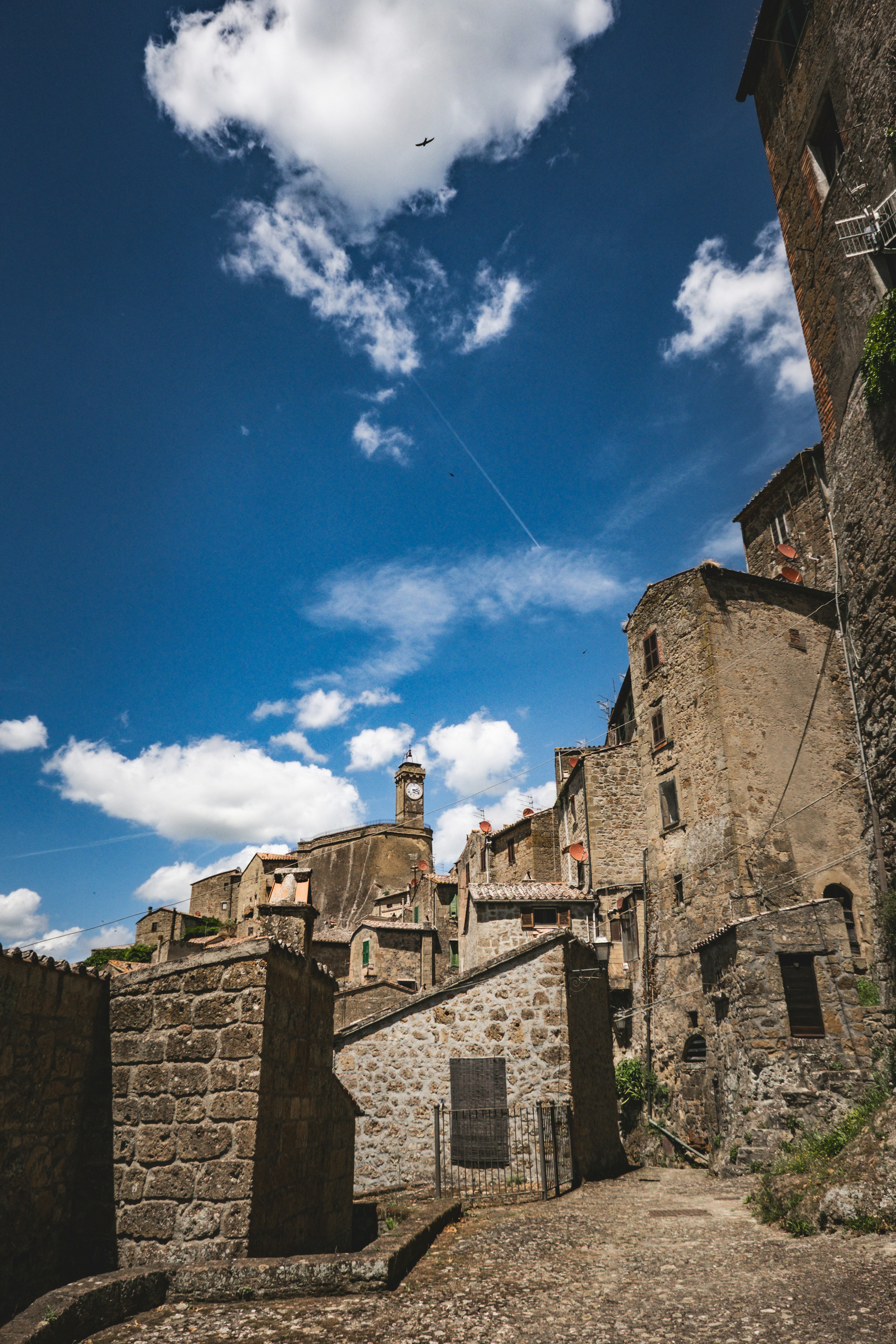 Old stone village with clock tower under a blue sky.