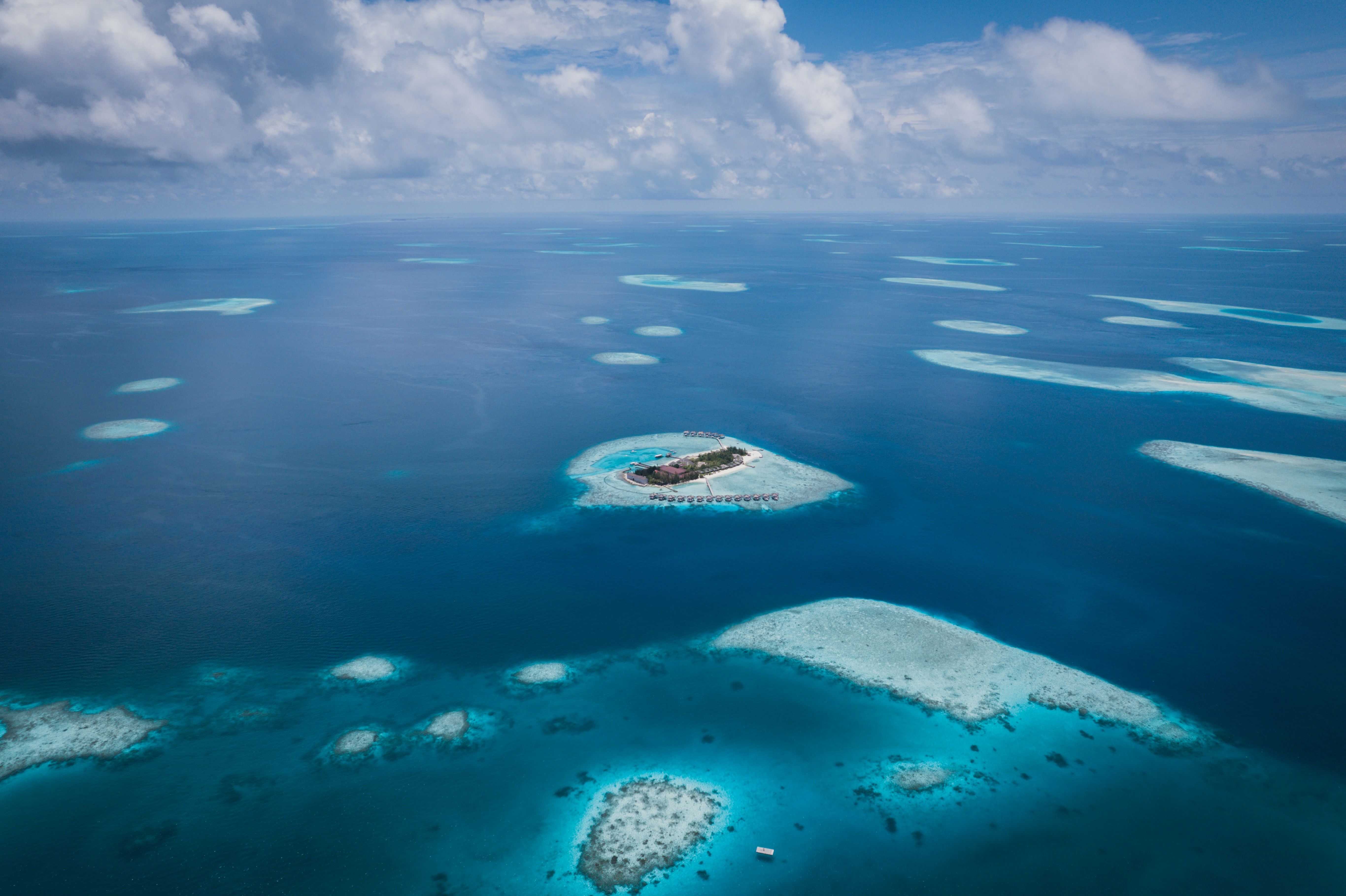 Vast tropical ocean with scattered islands and coral reefs.