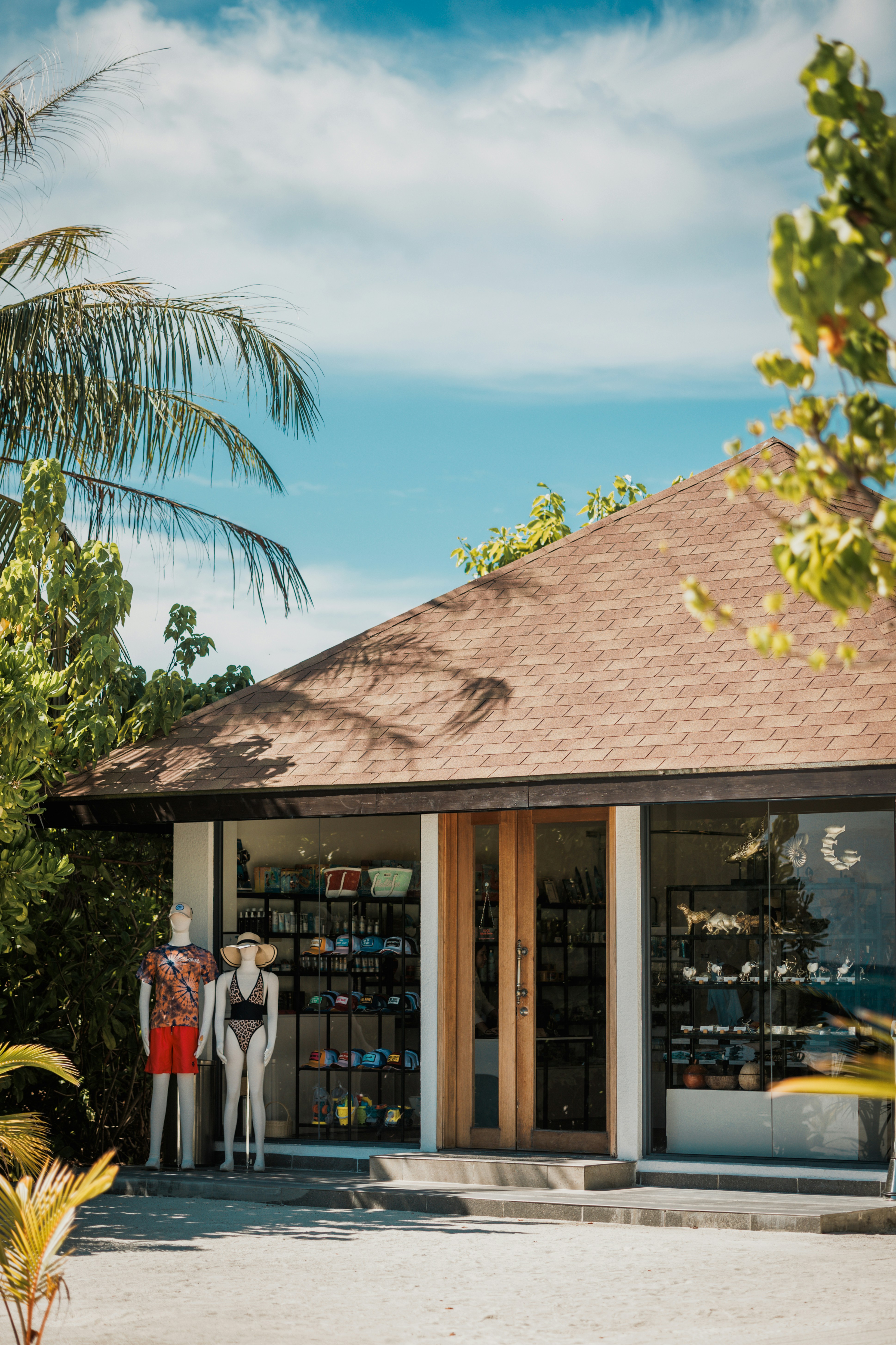 Shopfront with mannequins under a sunlit thatched roof