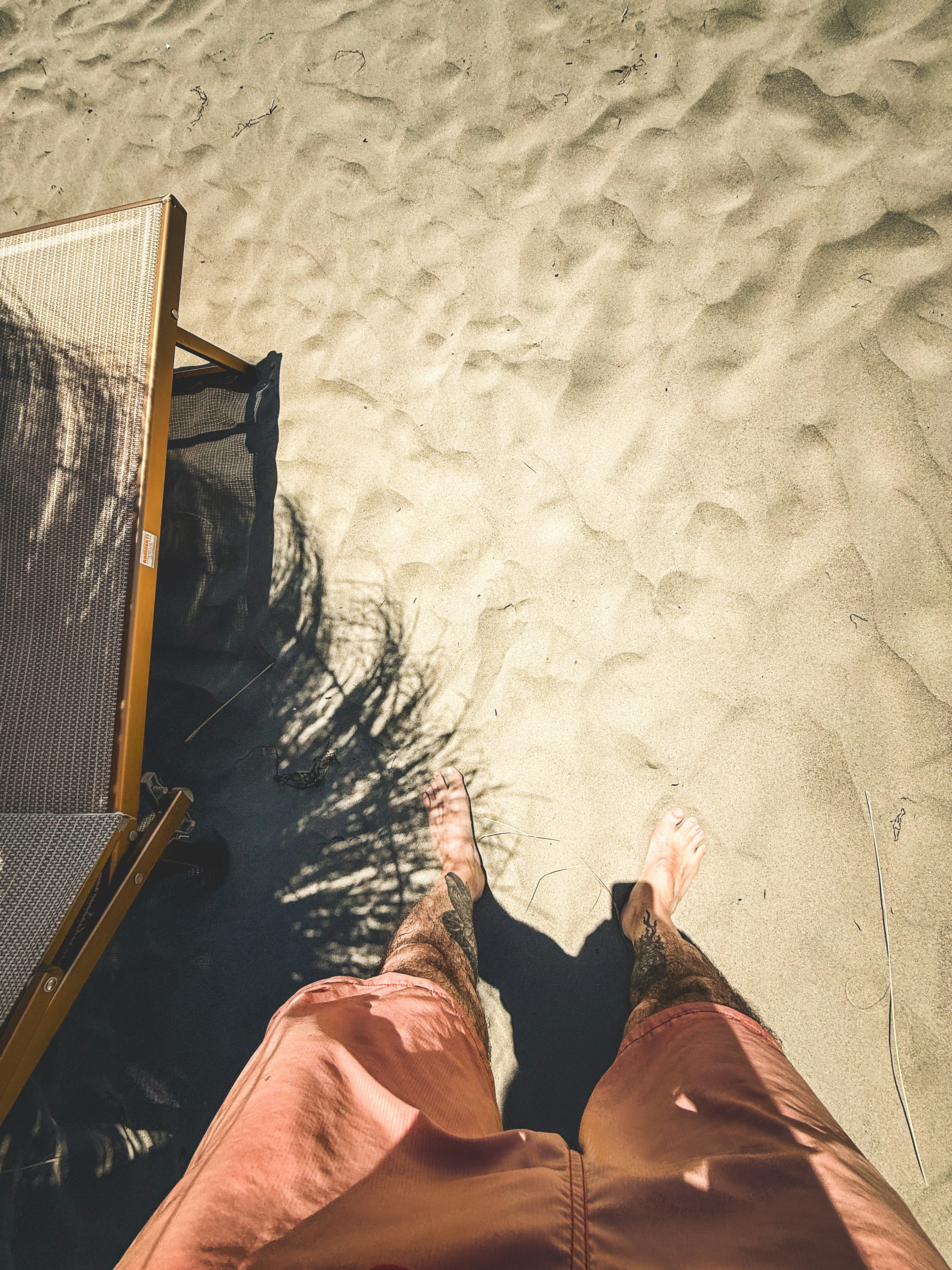 Legs and shadow on a sunny sandy beach.
