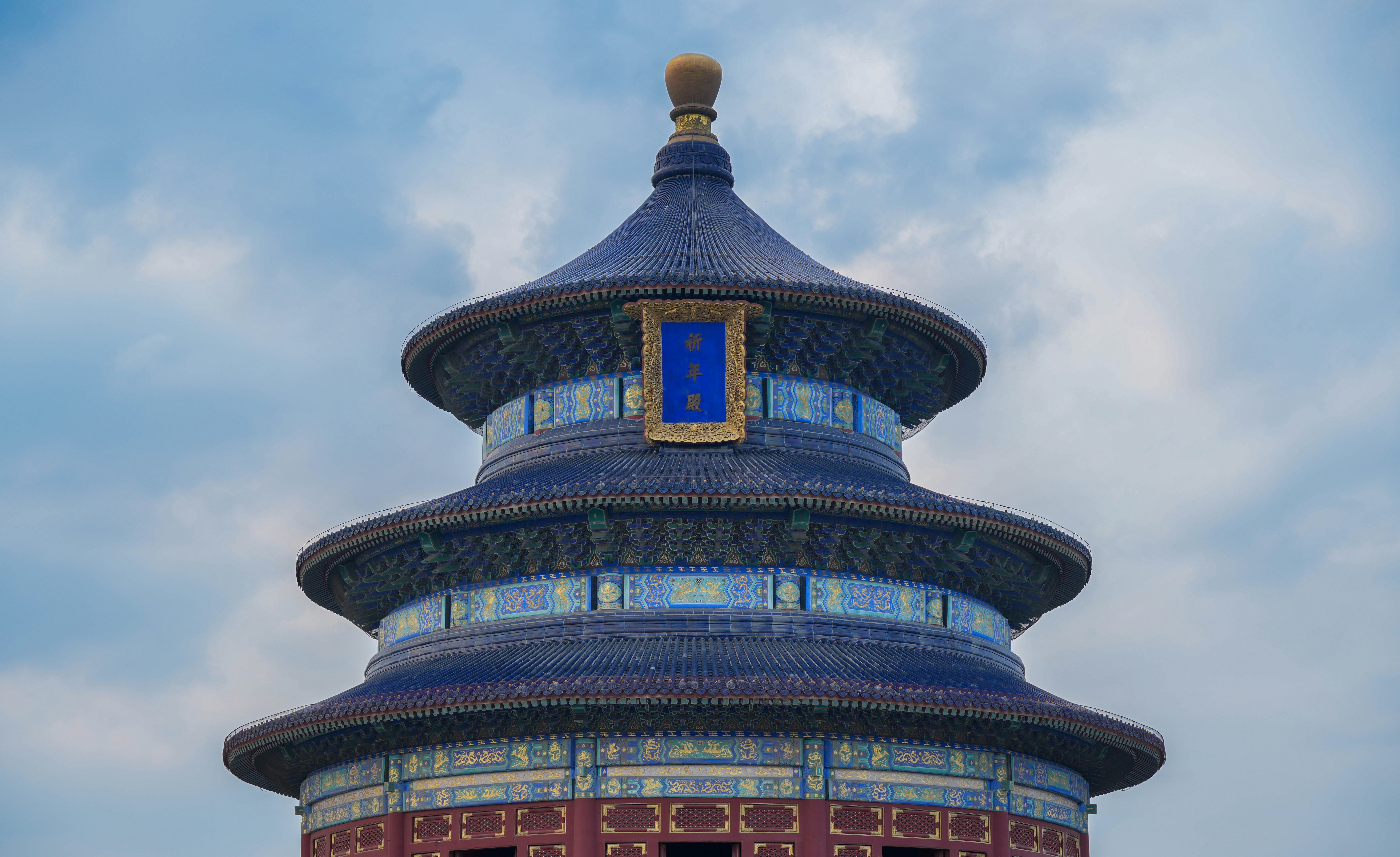 Tiered Blue Pavilion Reaching Toward a Cloudy Sky