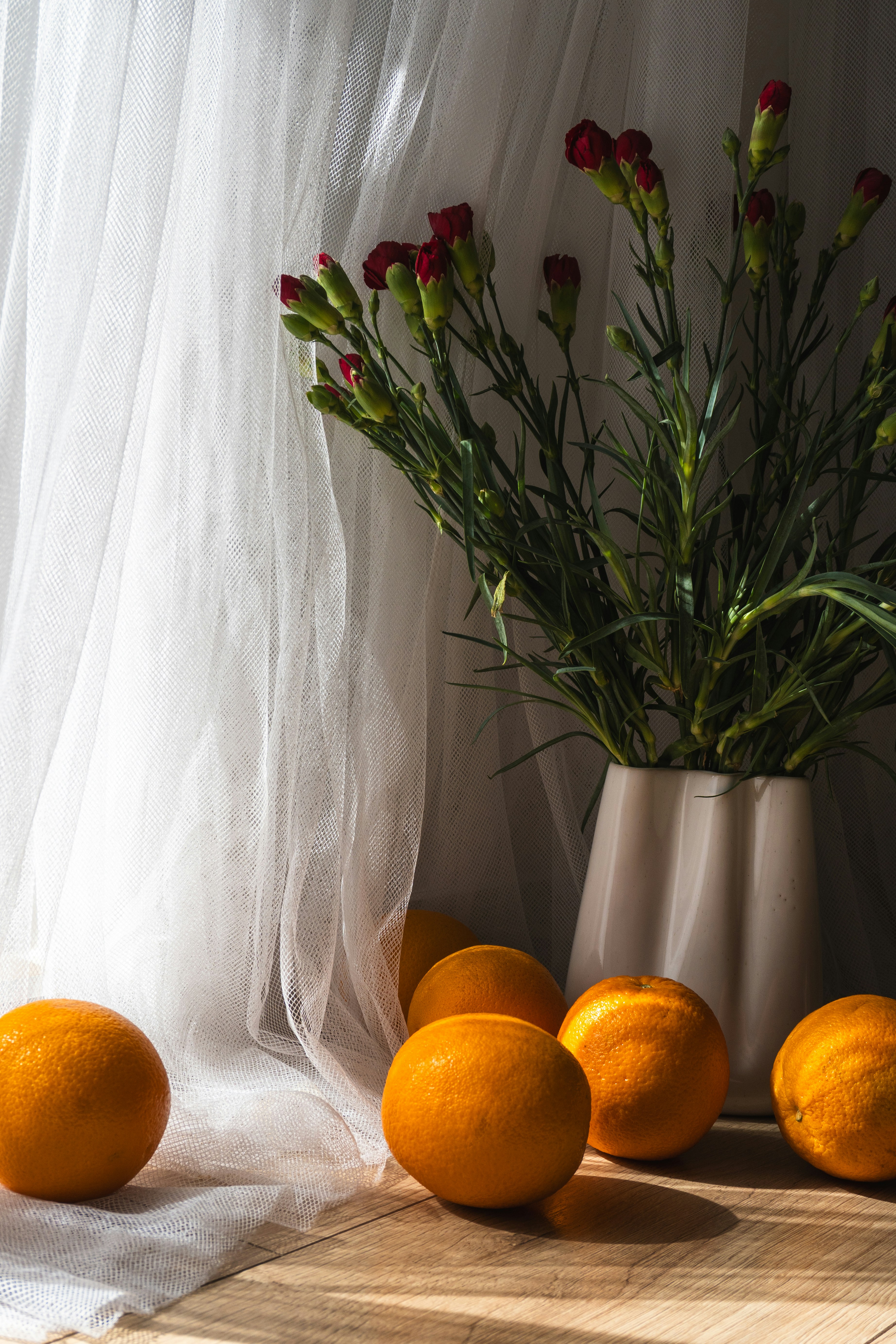 Citrus still life by window light with a vase of blooms
