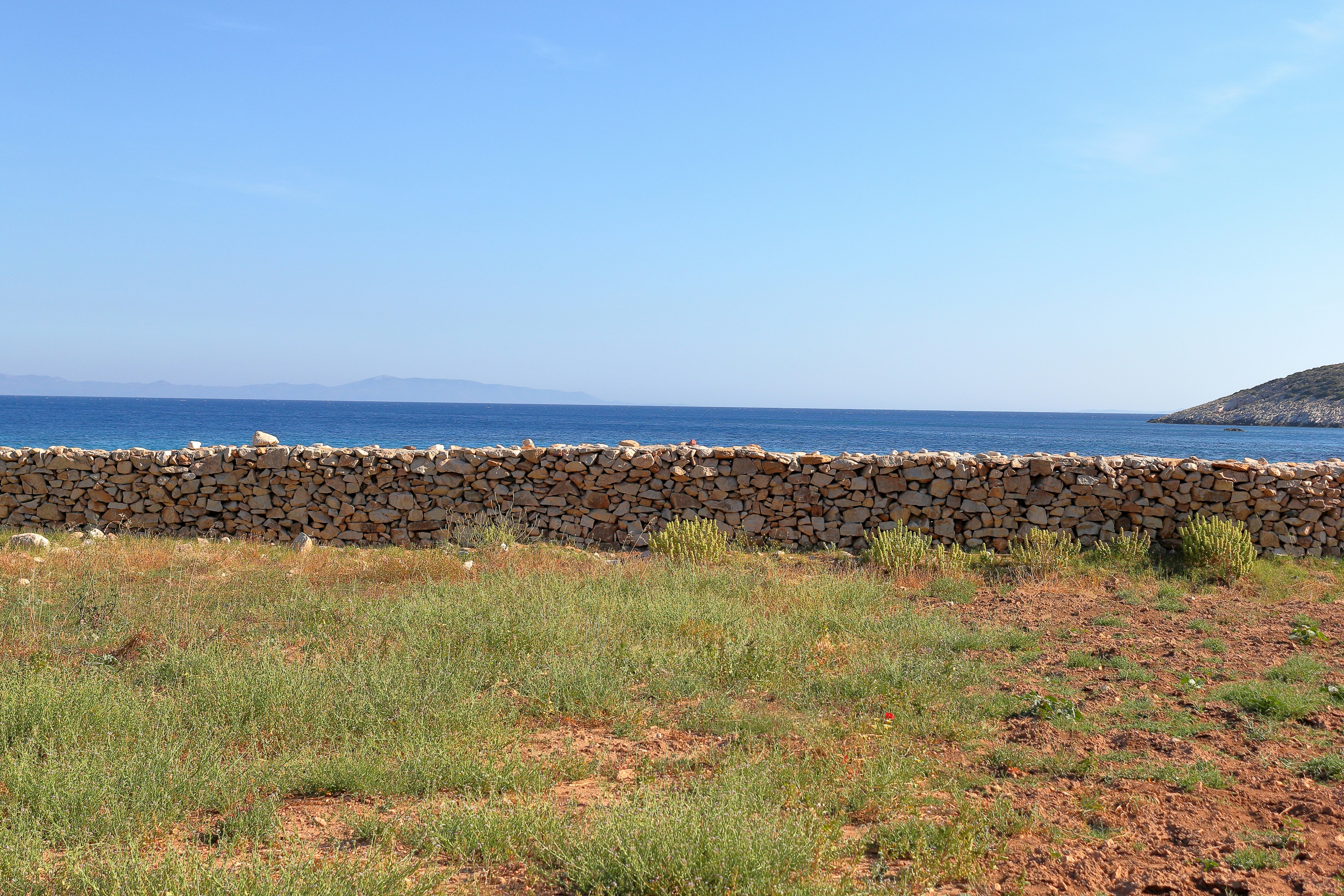 Stone barrier and coastline under a calm blue sky