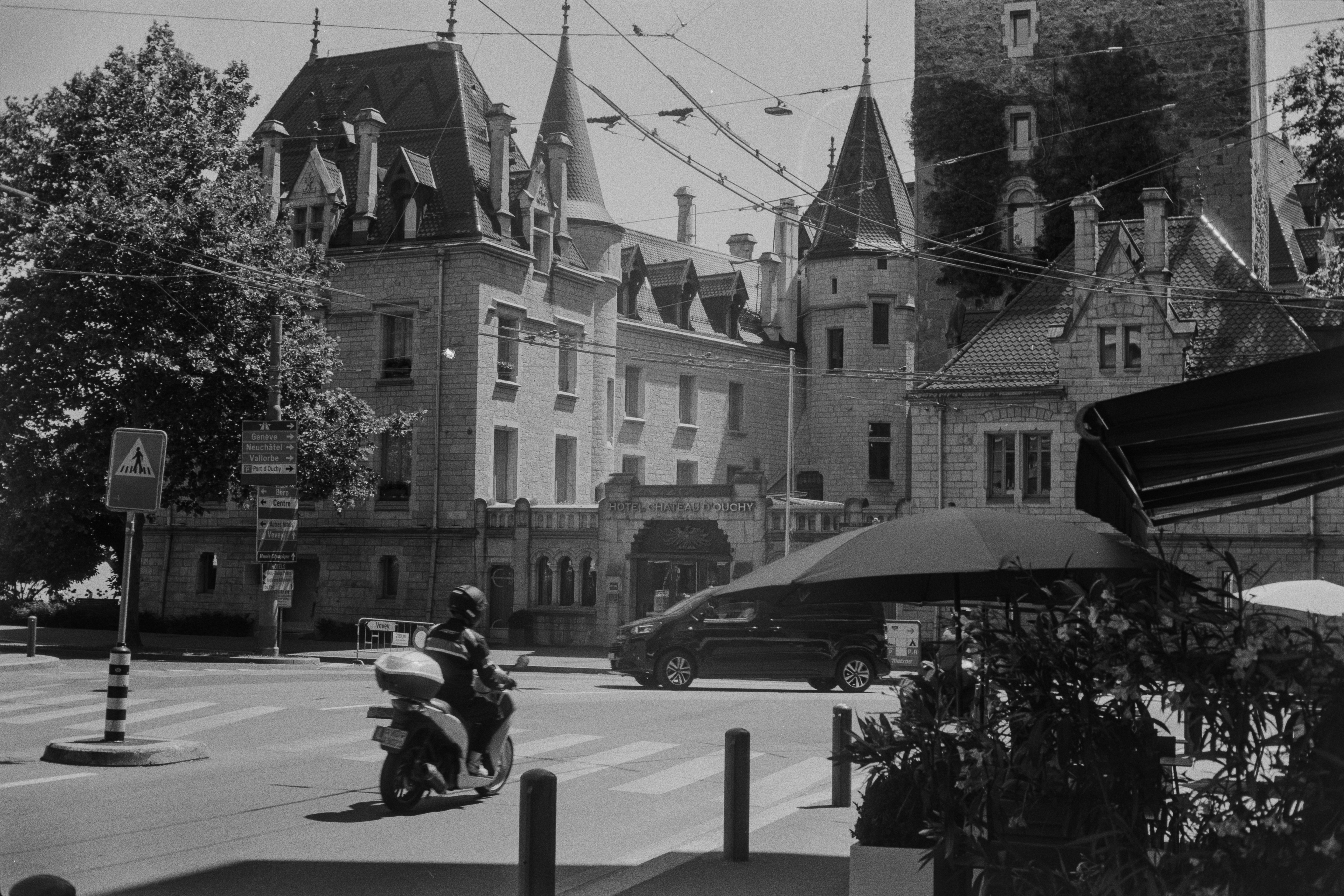 Cityscape in Motion: Scooter Crossing Beneath Medieval Rooftops