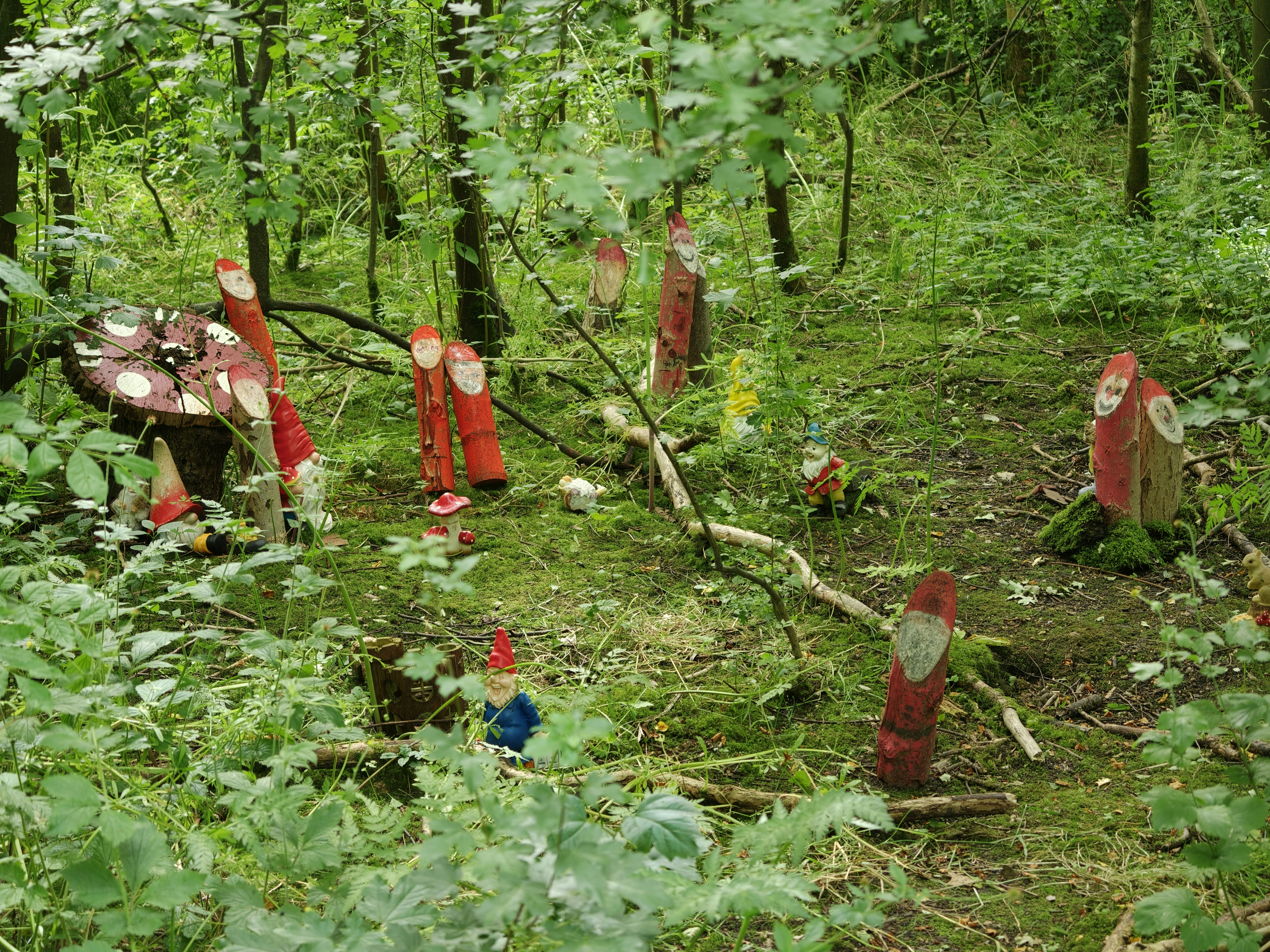 Red carved totems emerge from a mossy forest floor