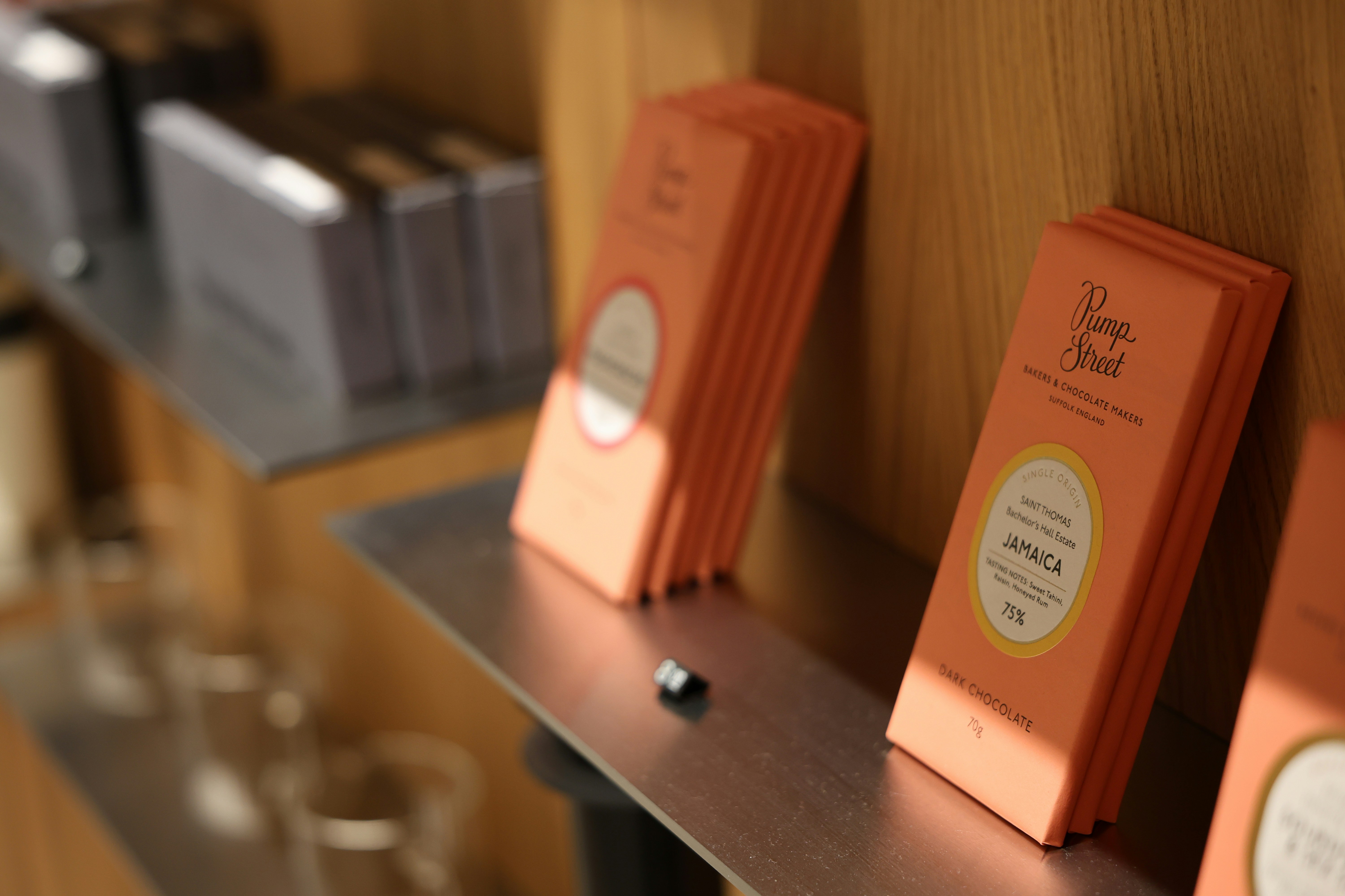Orange packaged chocolate bars stacked on a metal shelf.