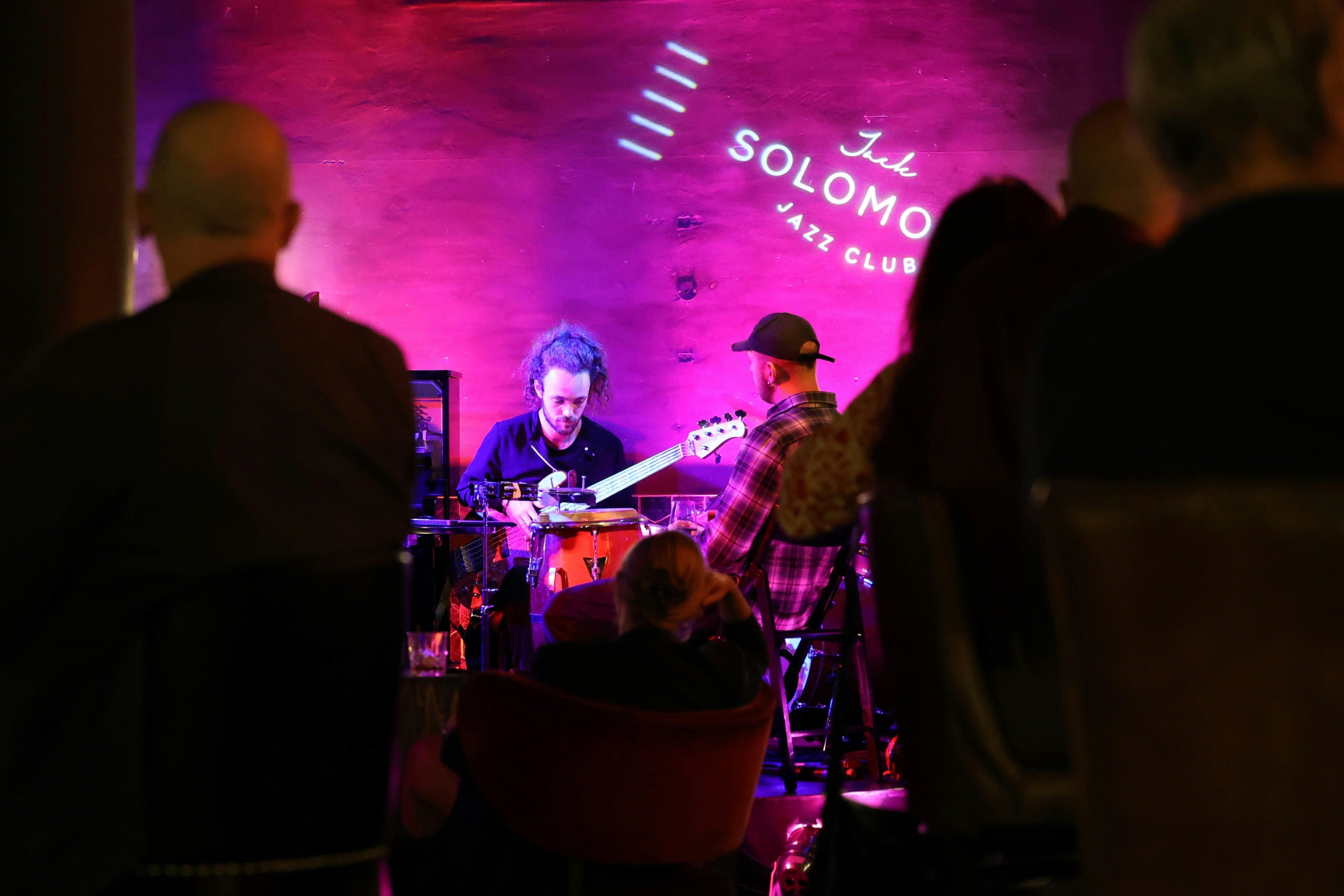 Midnight Jazz: Bassist Beneath Neon Solomo Club Sign