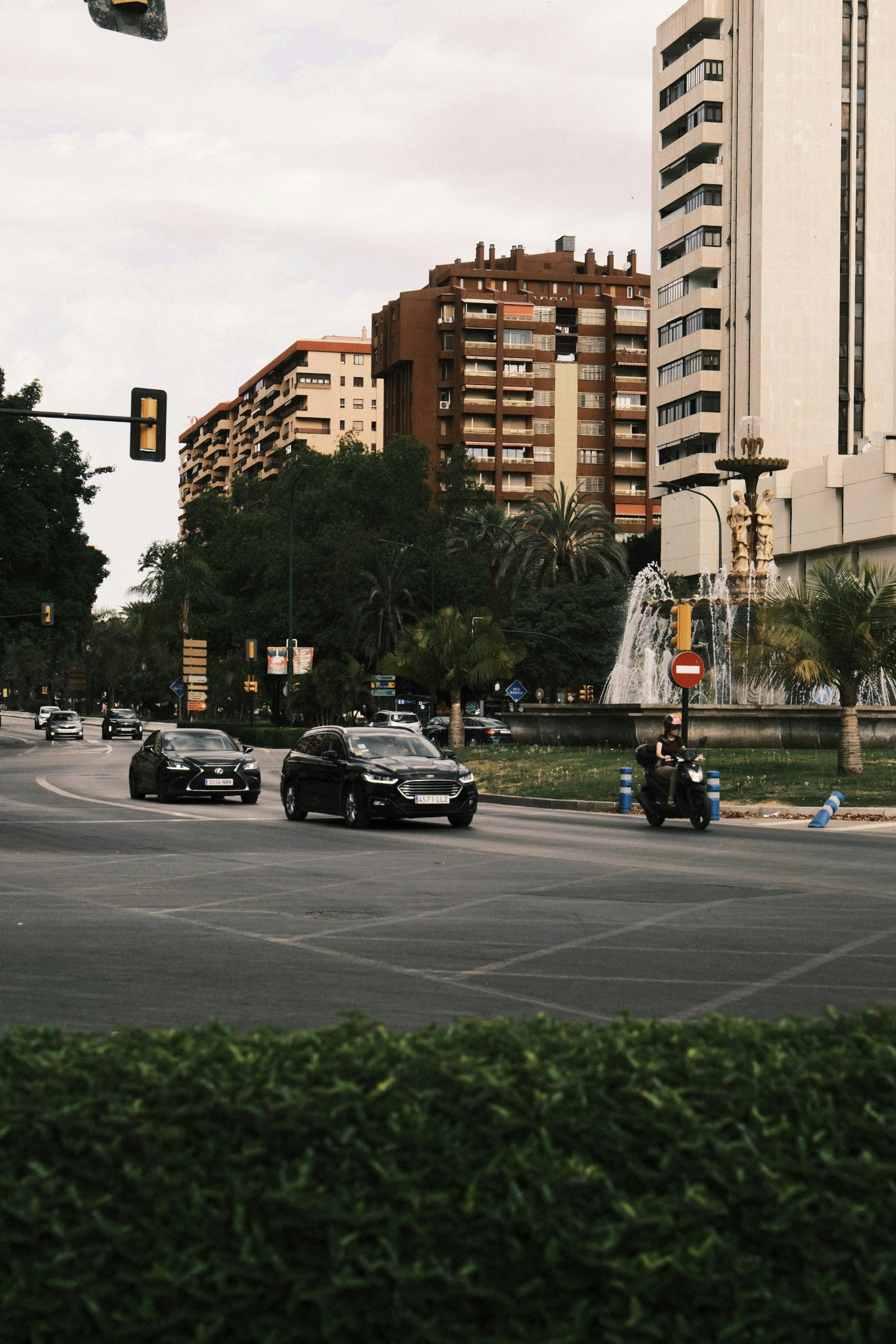 Urban Intersection: Cars, Fountain, and Tall Buildings at Dusk