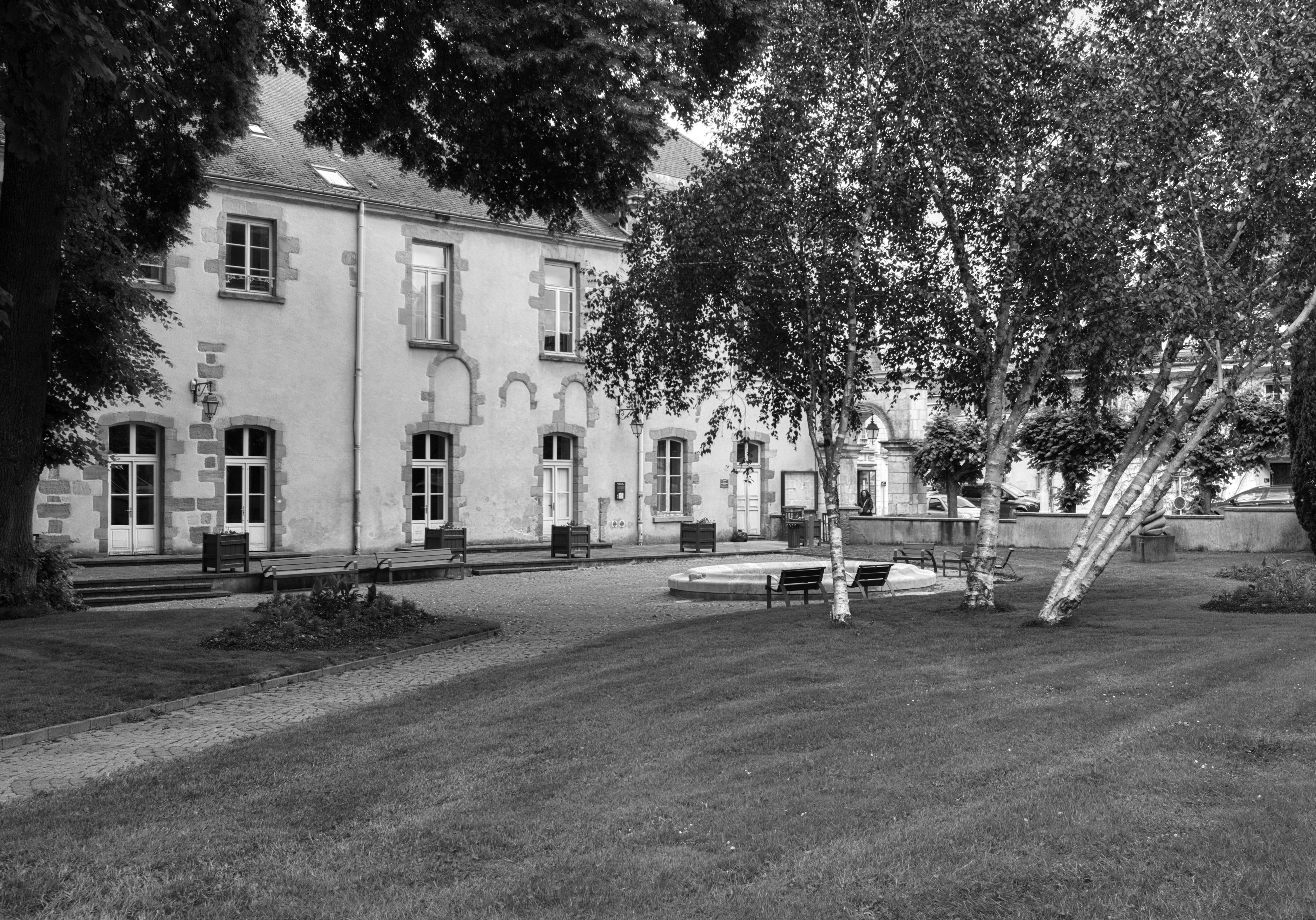 Sunlit Courtyard Facade: Historic Building Among Shade and Lawn