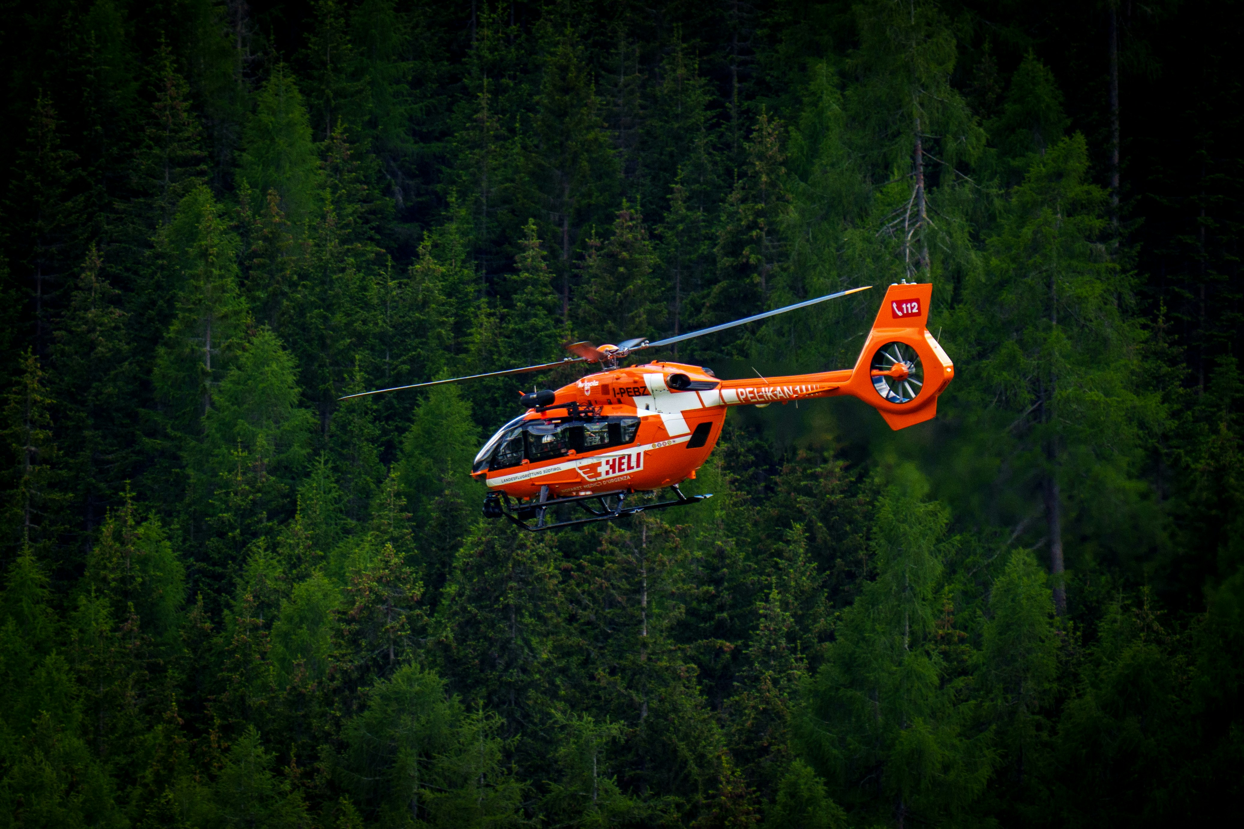 Orange Rescue Helicopter Slices Through Dense Alpine Canopy