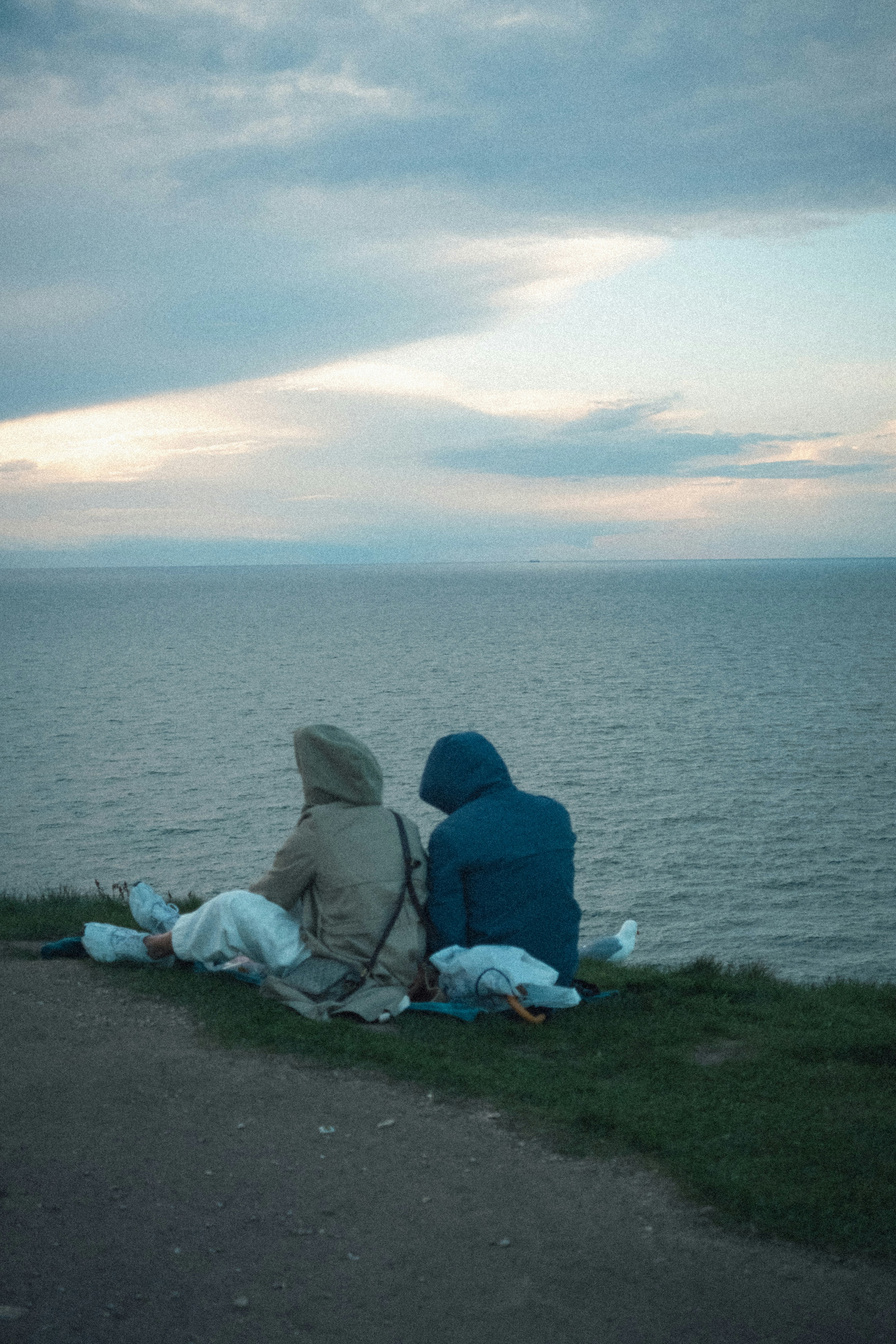 Two Hooded Figures Share Quiet Horizon by the Sea