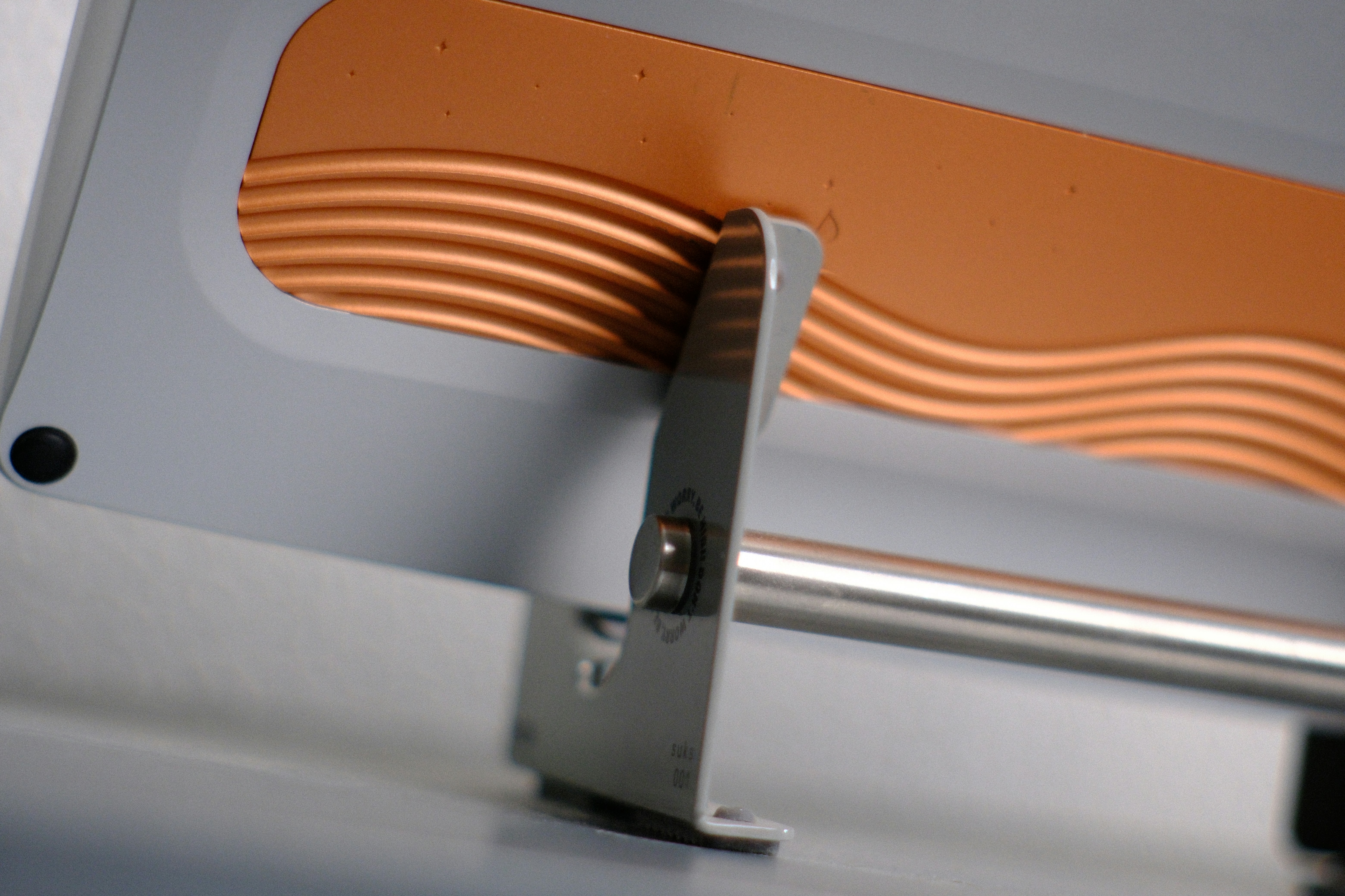 Close-up of a copper coil winding secured by a metallic bracket within a precision mechanical assembly.