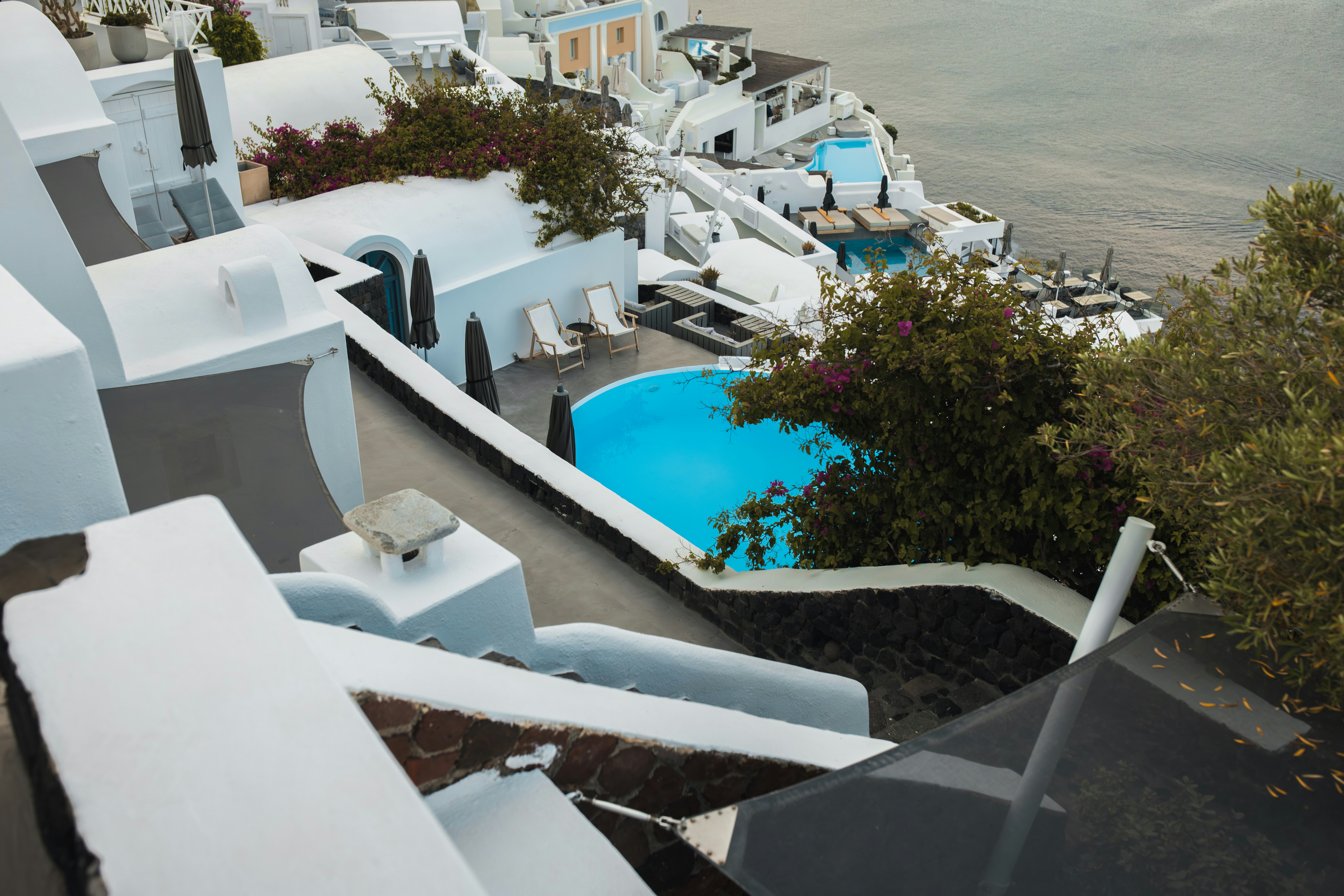 Aegean Cliffside: Whitewashed Terraces Adorned by a Blue Oasis