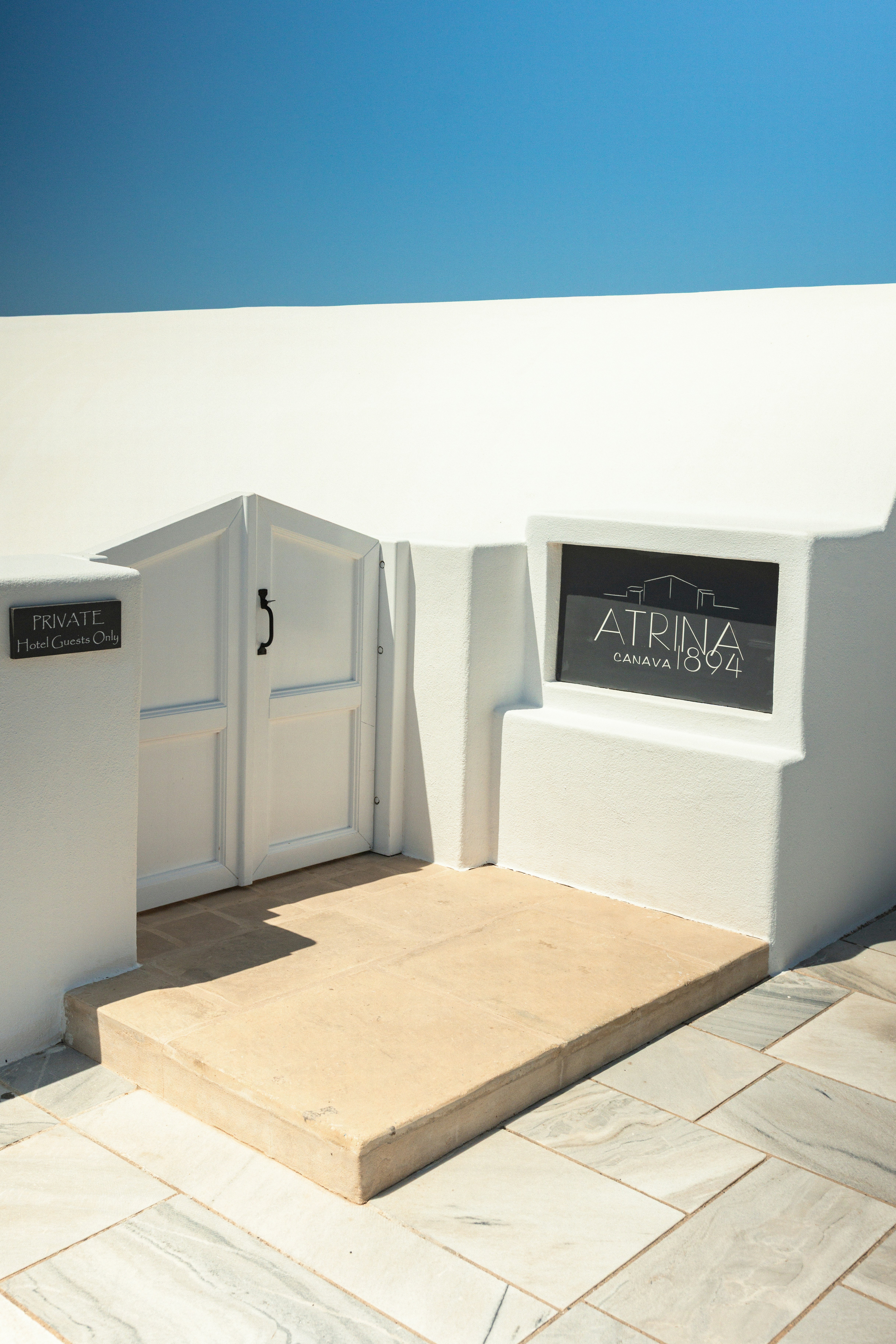 Whitewashed Entryway to Atrina Hotel under Aegean Sky