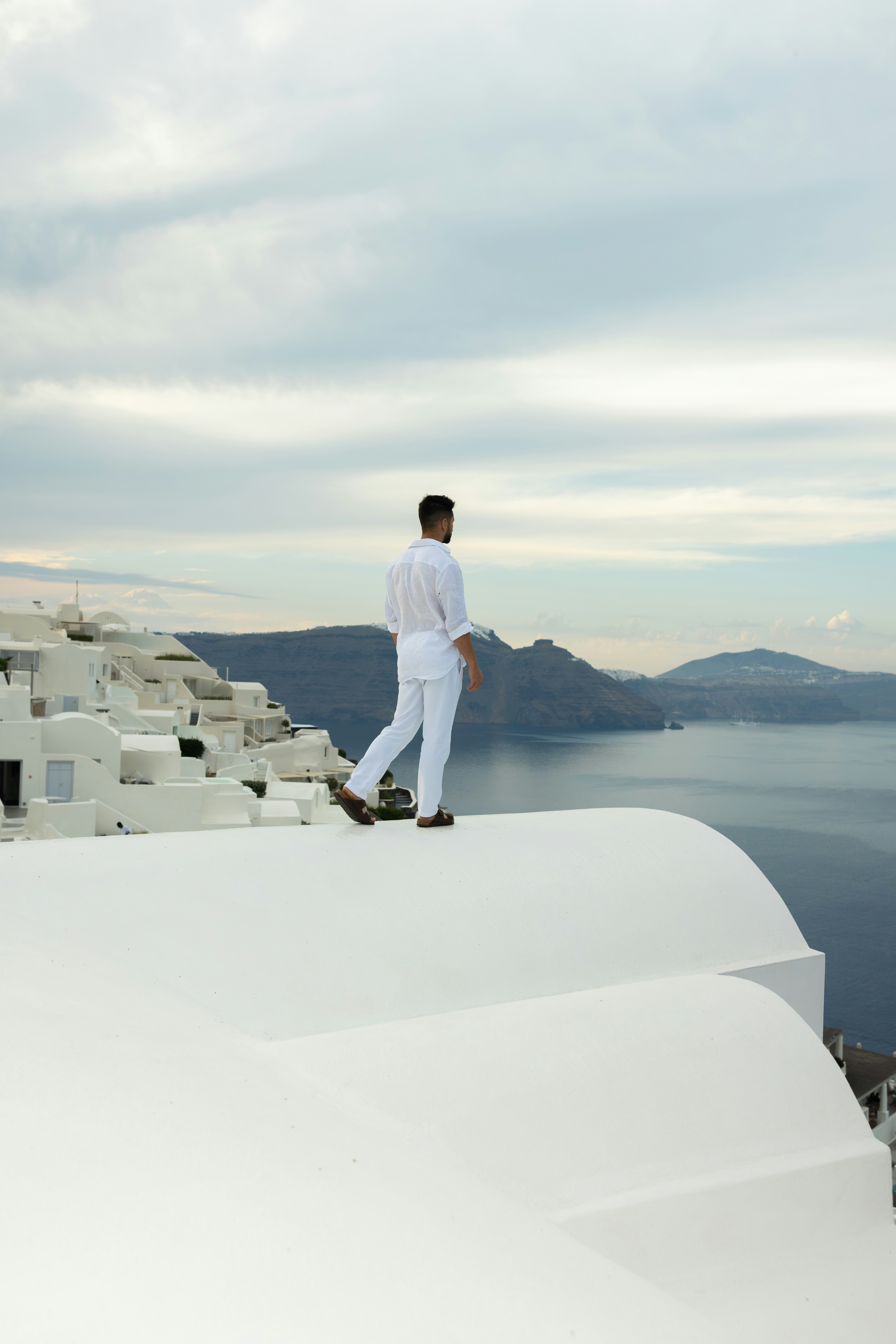 Terrace of Light: A White-clad Wanderer on Santorini's Edge