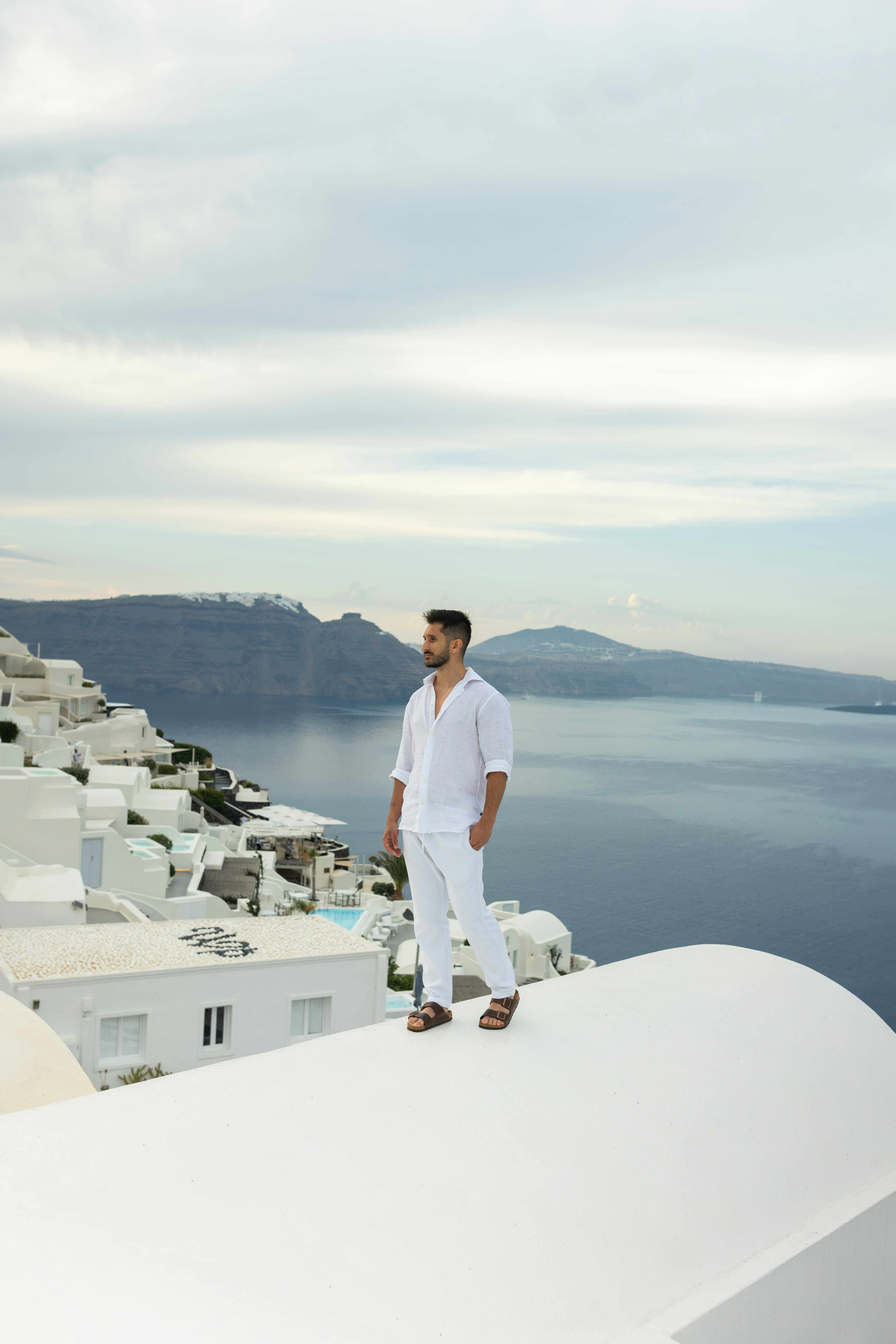 White Linen Horizon: Man in White Overlooking Aegean Cliffs