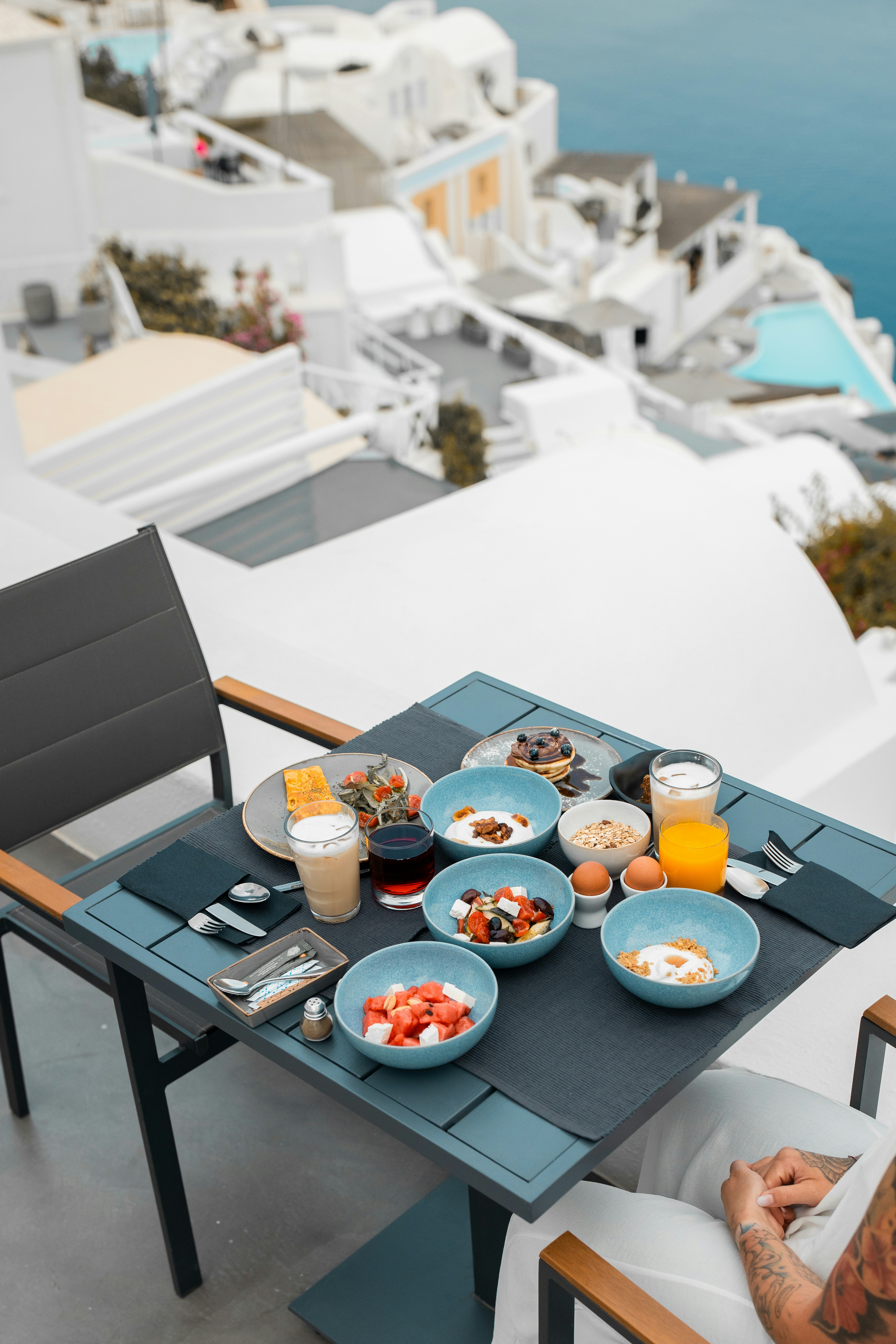Blue ceramic bowls and sunny breakfast on a terrace overlooking Aegean whitewashed rooftops