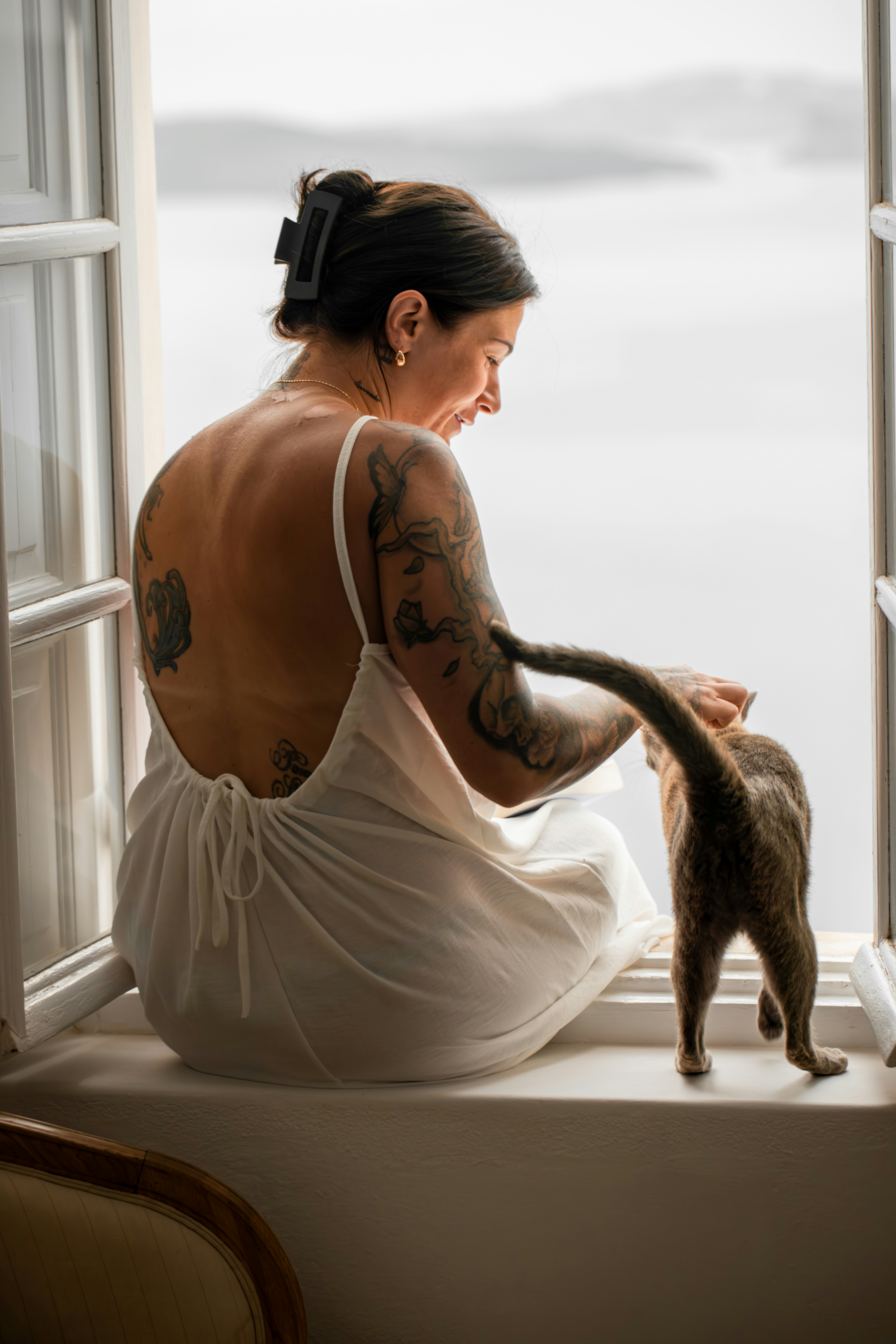 Tattooed silhouette by the window with a curious cat