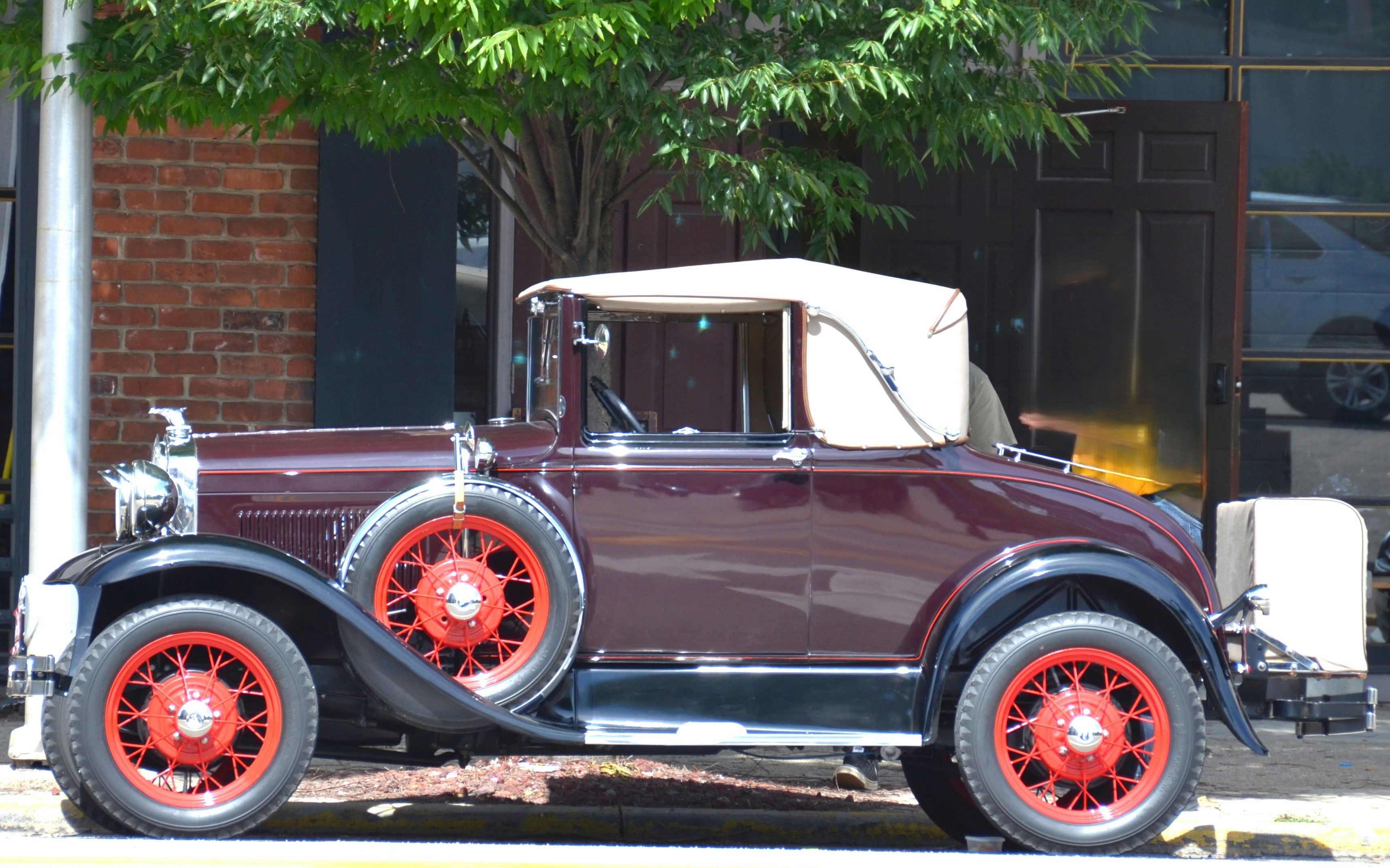 Crimson Wheels and Cream Canopy: A Vintage Convertible in Sunlit Still