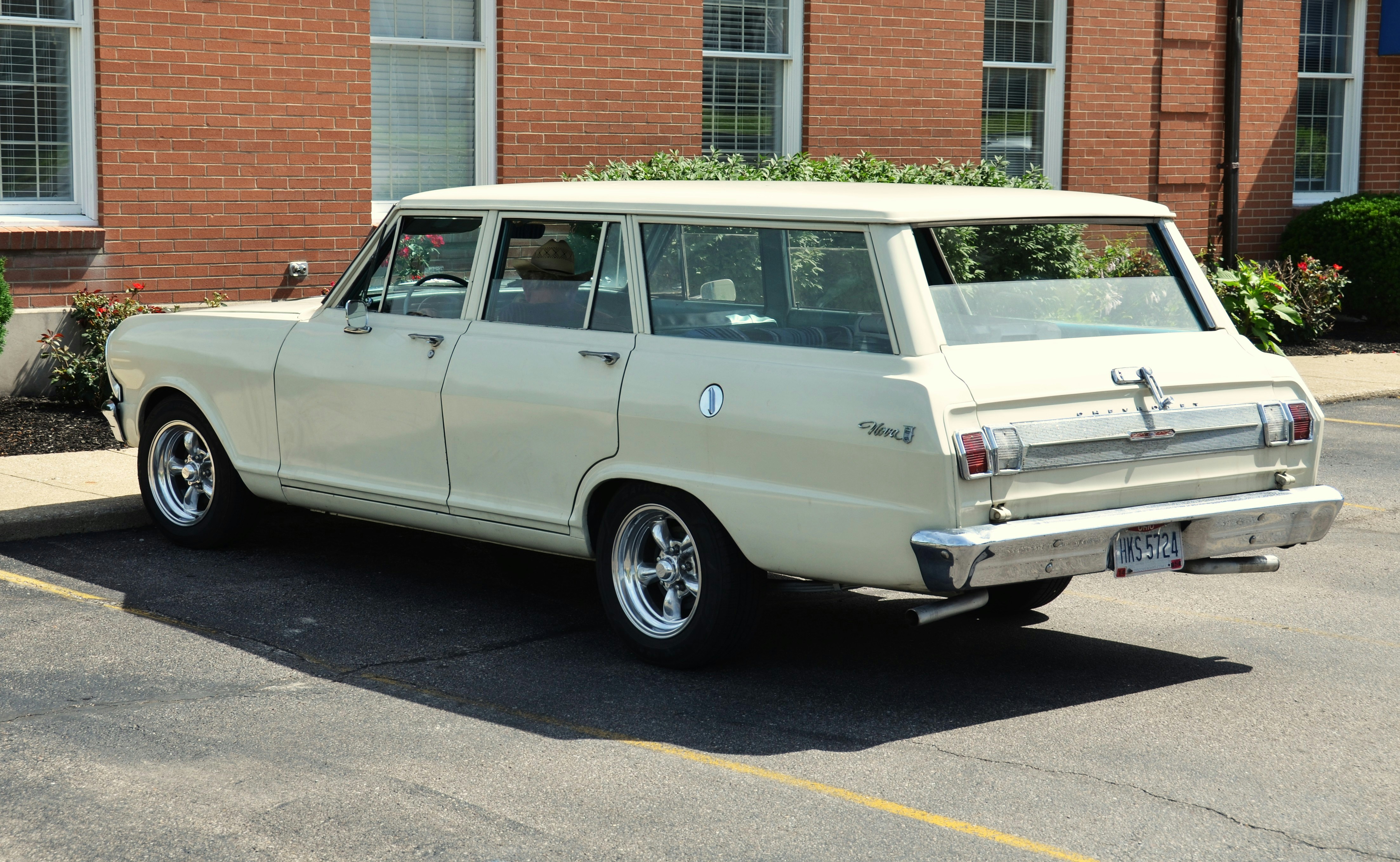 Cream-colored vintage station wagon parked beside a brick building
