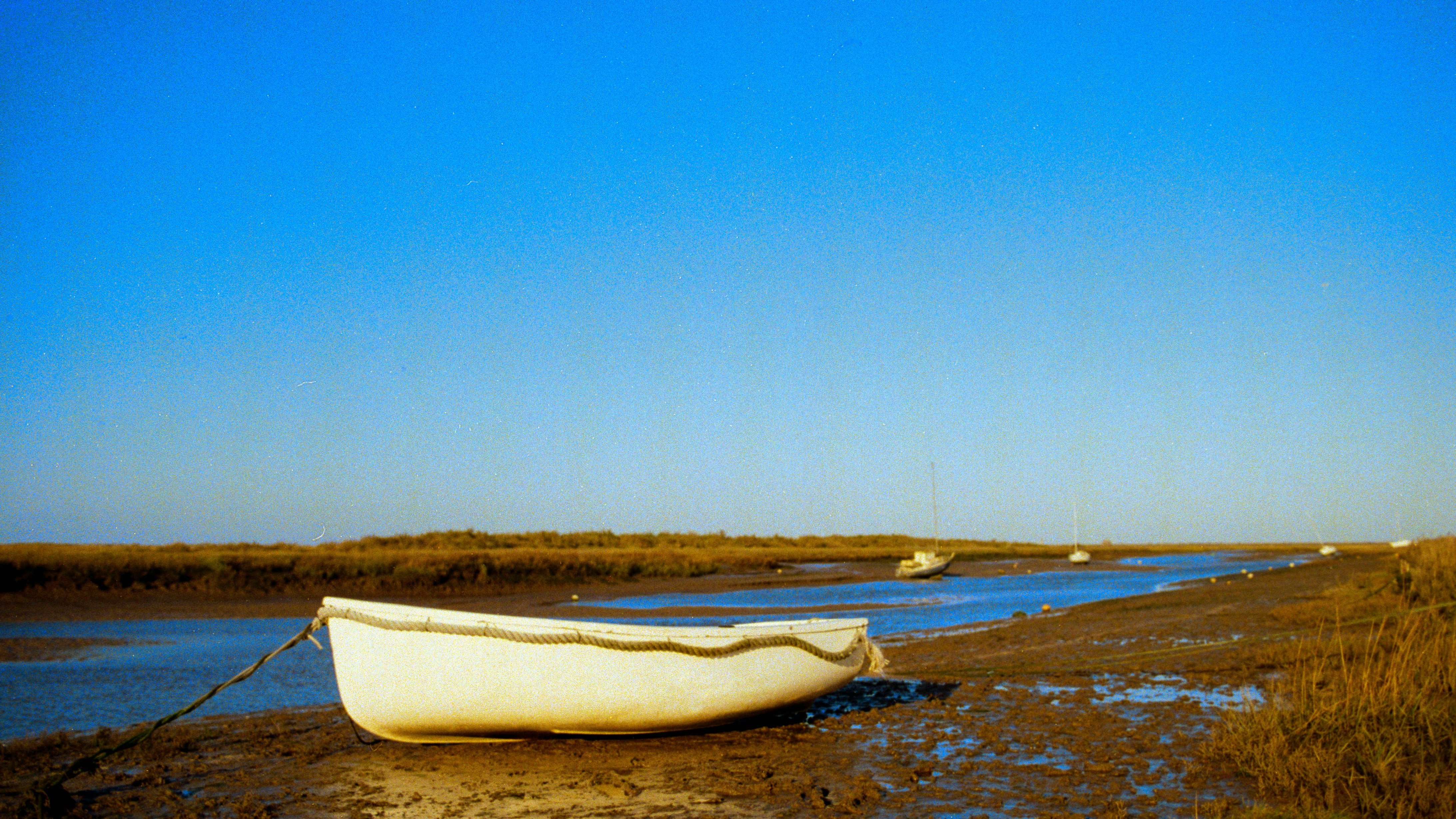 White Boat on Tidal Marsh under Wide Blue Sky