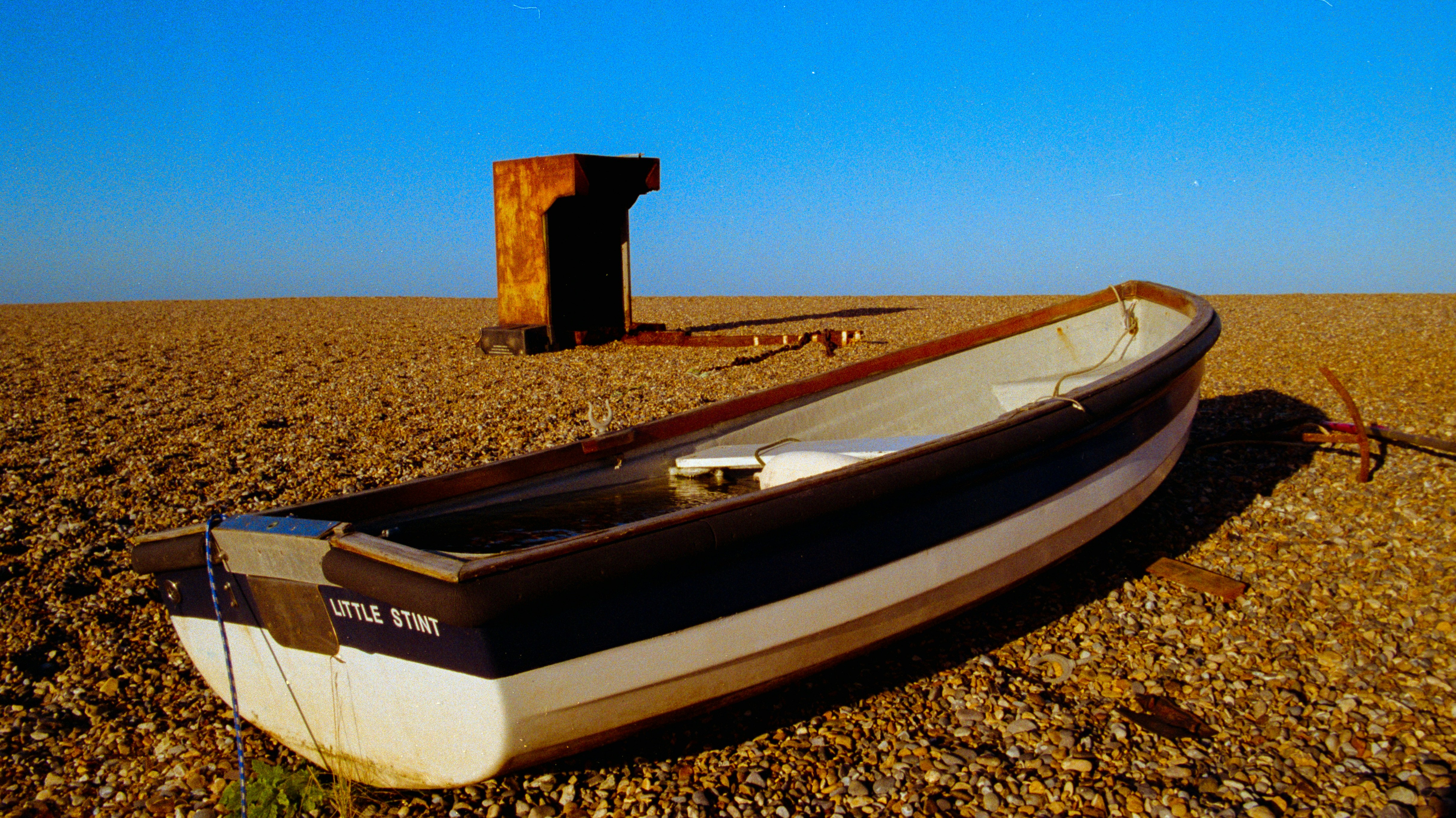 Low Tide Lullaby: A Small Boat Resting on Pebbled Shore