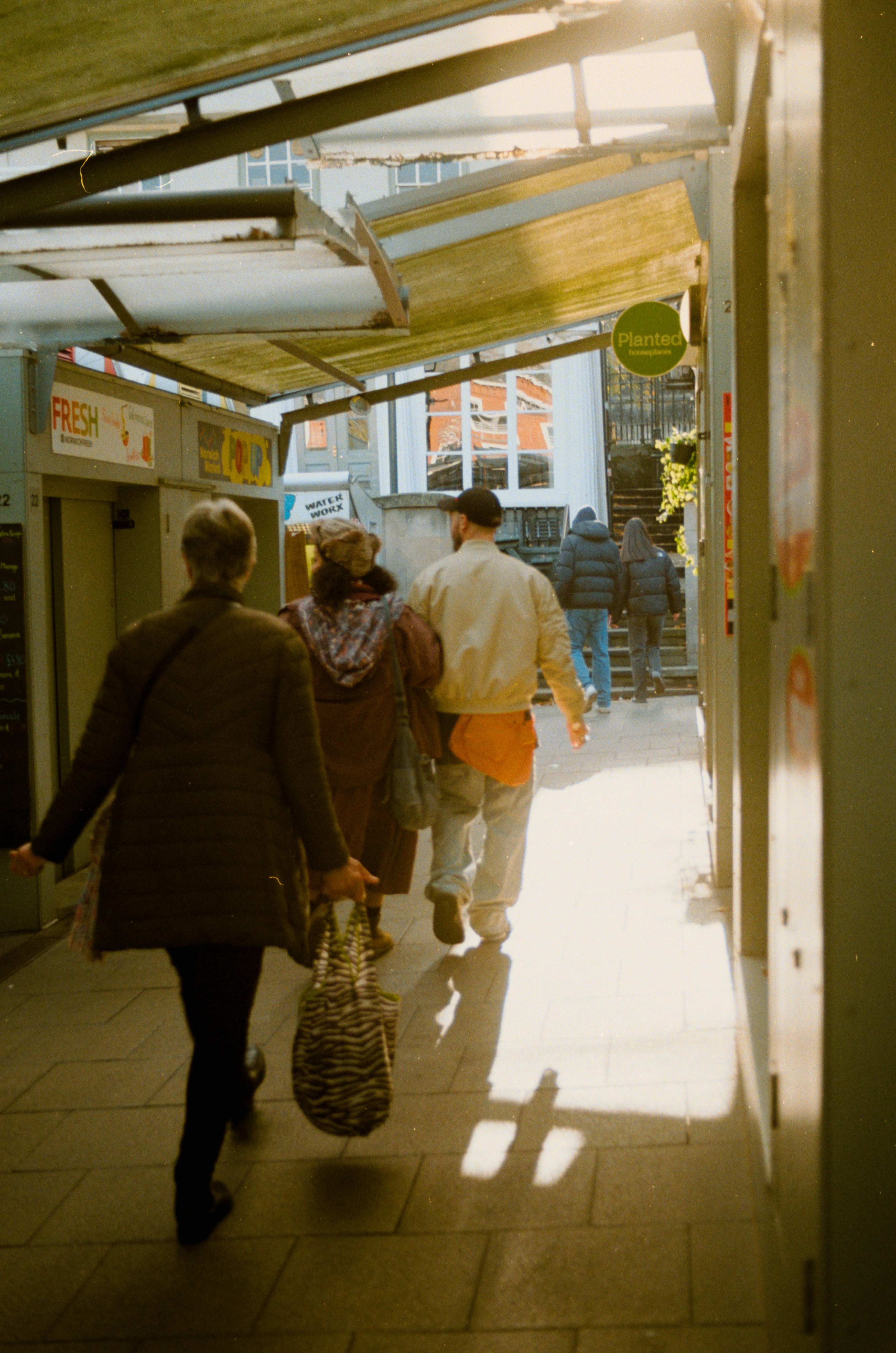 A Quiet City Walk: Shaded Alleyway Amid Busy Foot Traffic