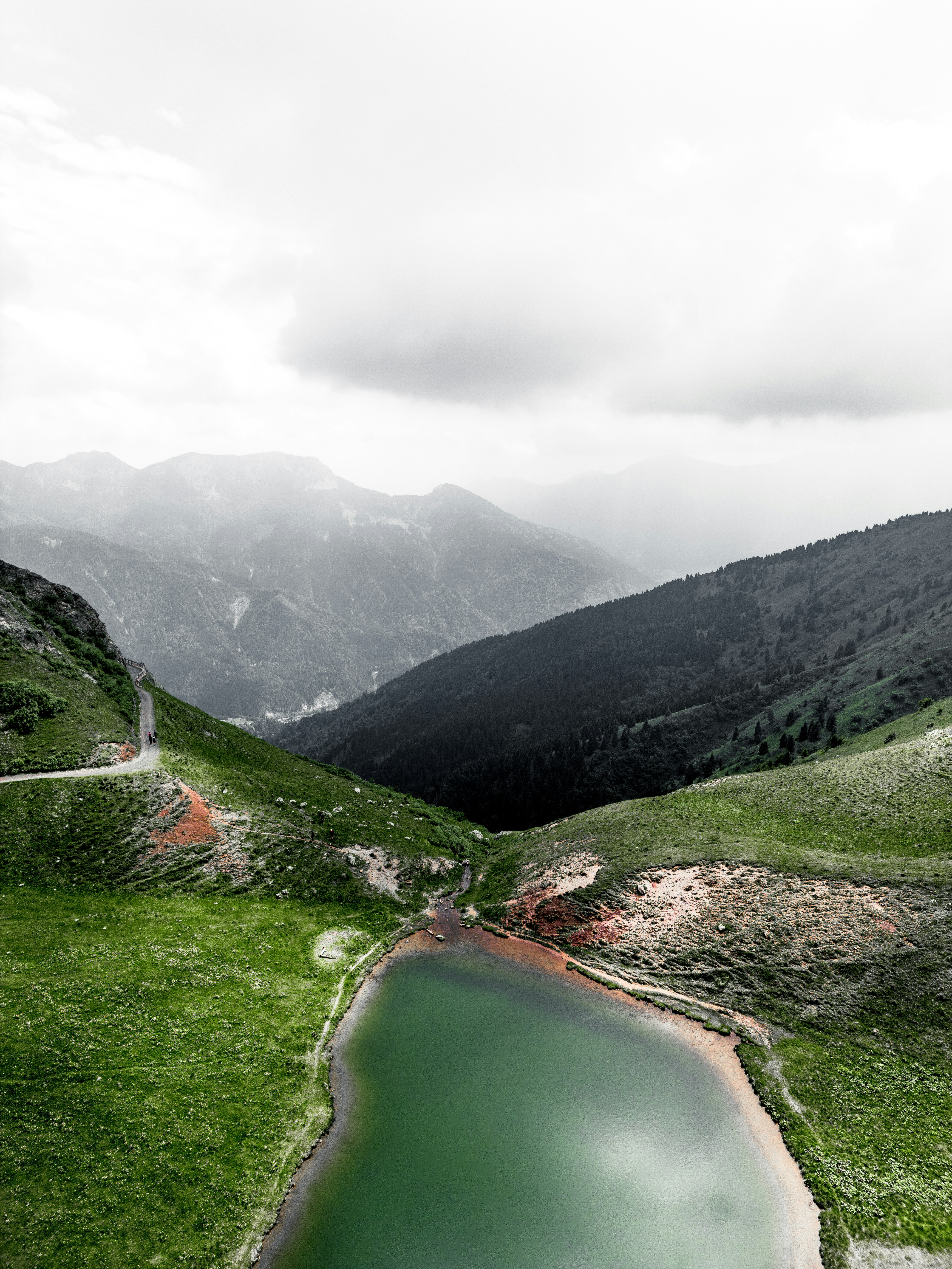 Tranquil green lake in a mountain valley under overcast skies.