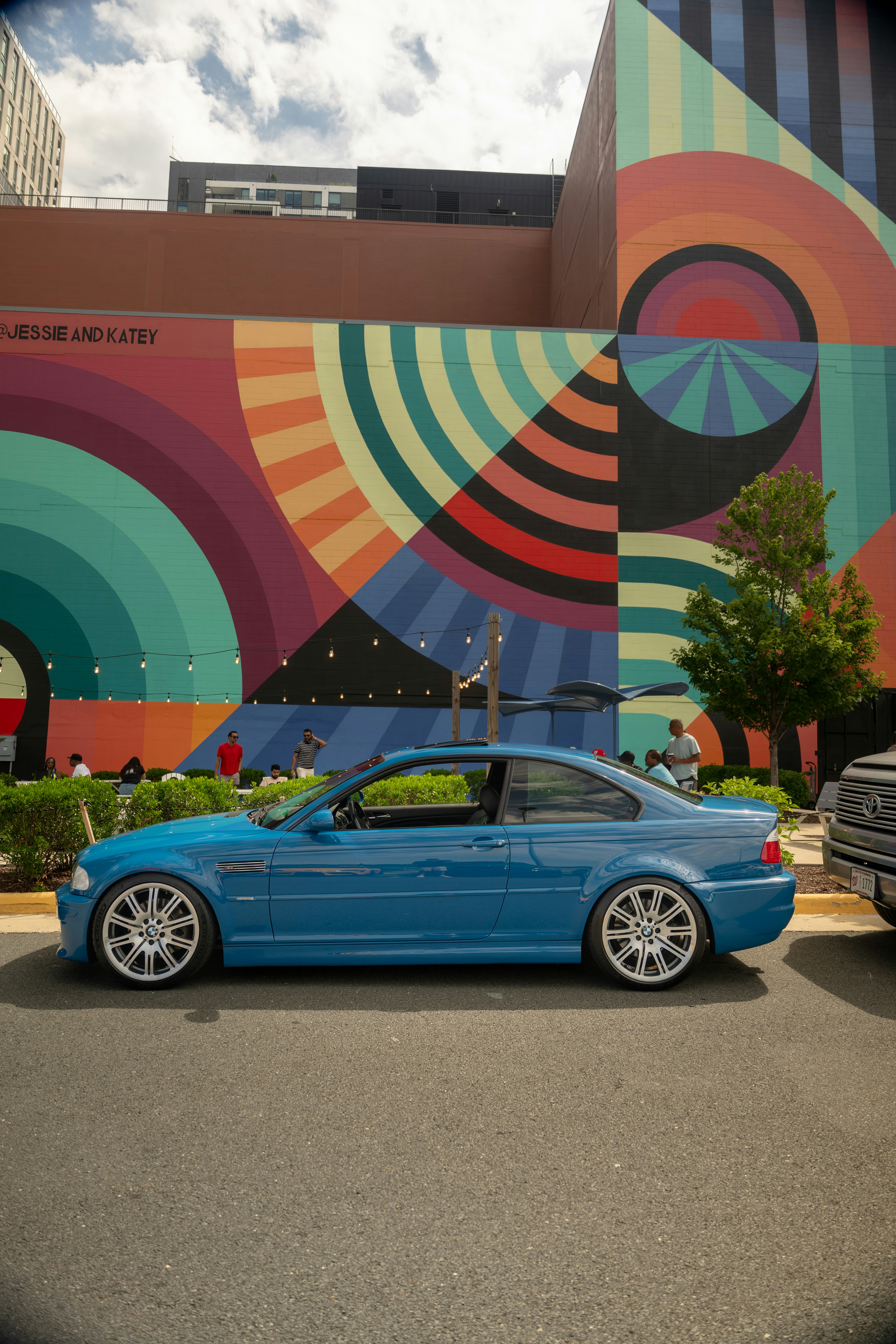 Blue Coupe Beneath a Kaleidoscopic Urban Mural