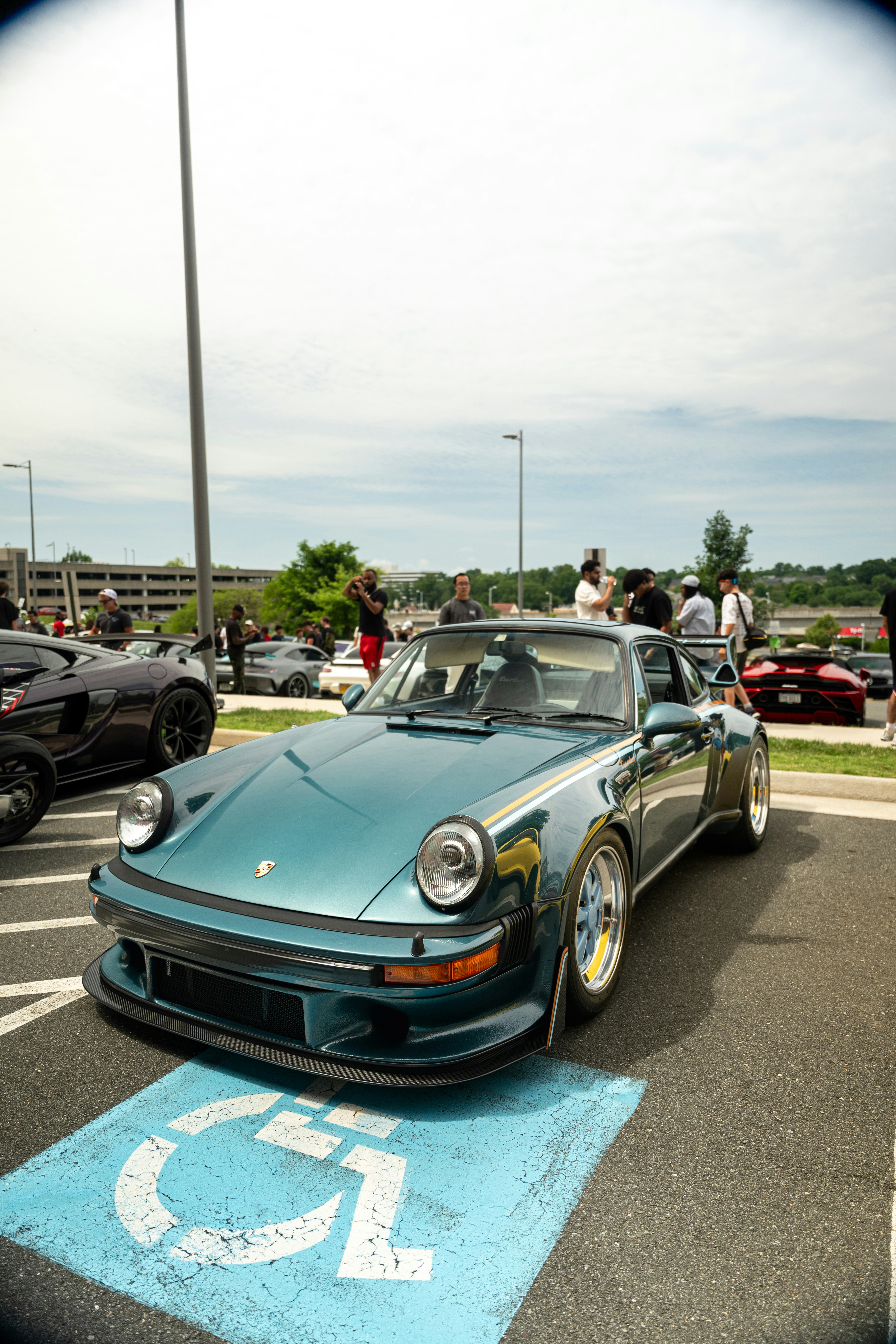 A teal vintage porsche car parked in a parking lot.