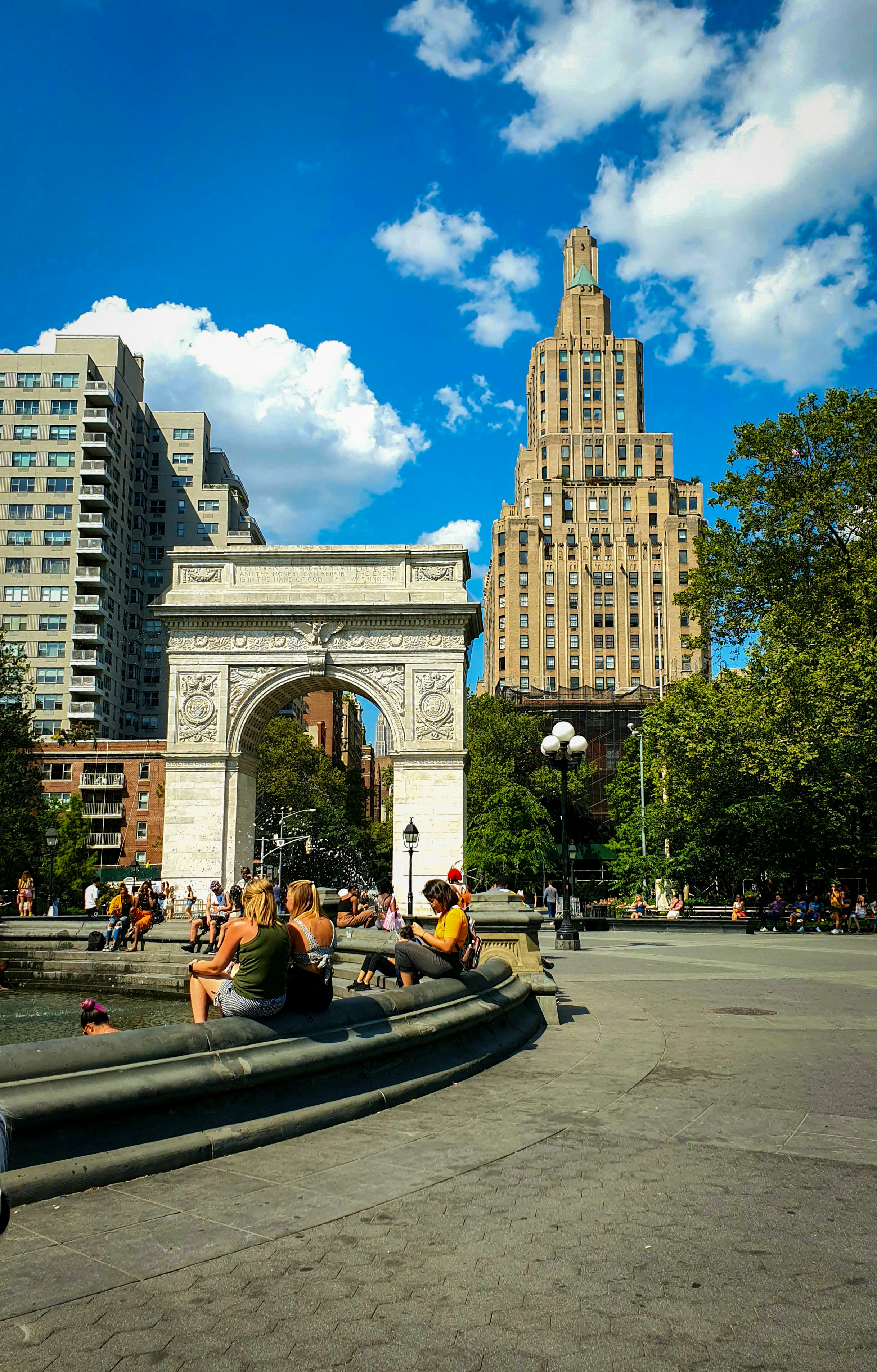 Washington square arch, fountain, and people on a sunny day.