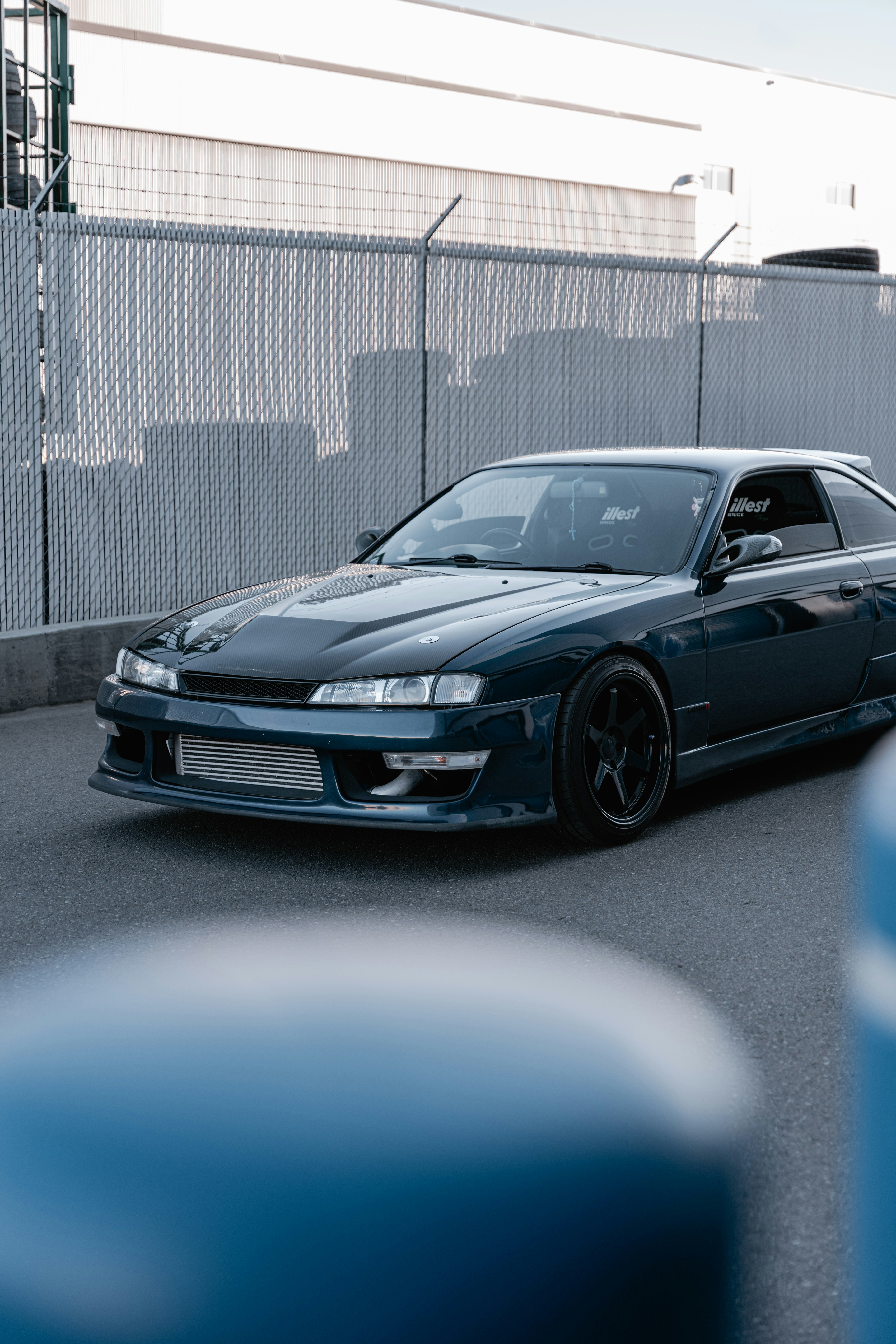 Low-Slung Street Warrior: A Dark Blue Drift Sleeper at the Fence Line