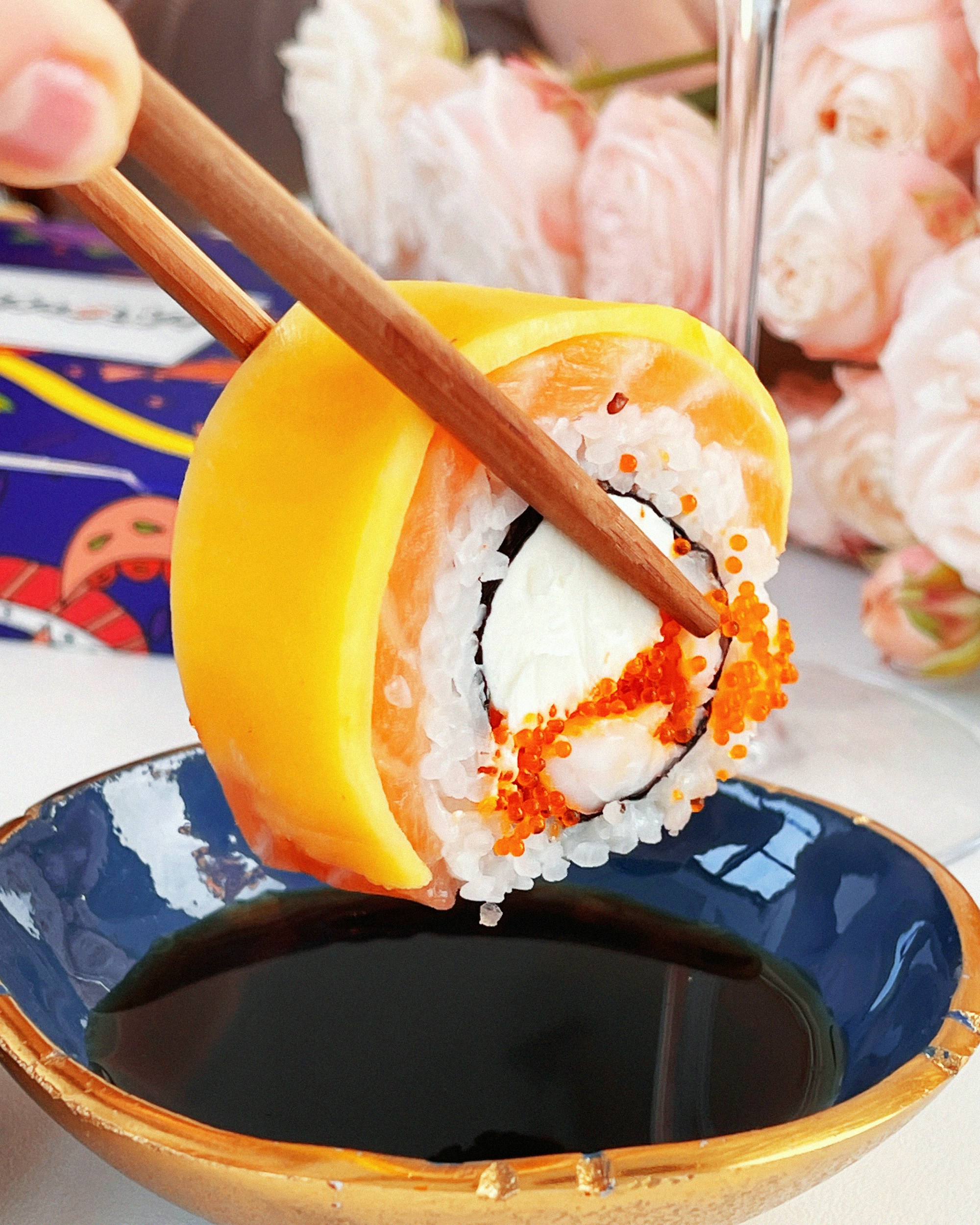 Chopsticks in Focus: A Mango-Covered Sushi Roll Dipping into Soy