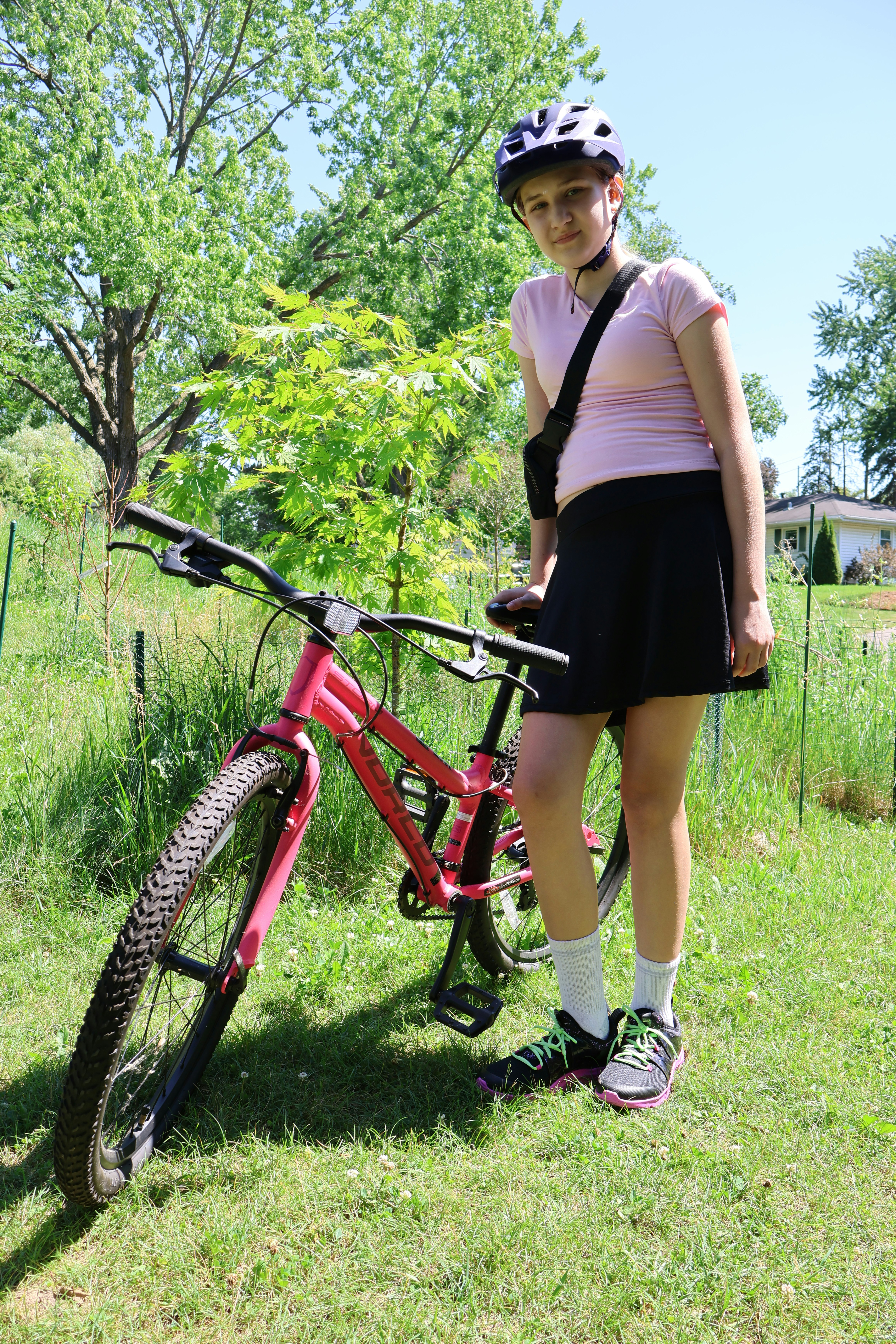 Portrait of a Cyclist with Pink Top and Red Mountain Bike in Sunlit Garden