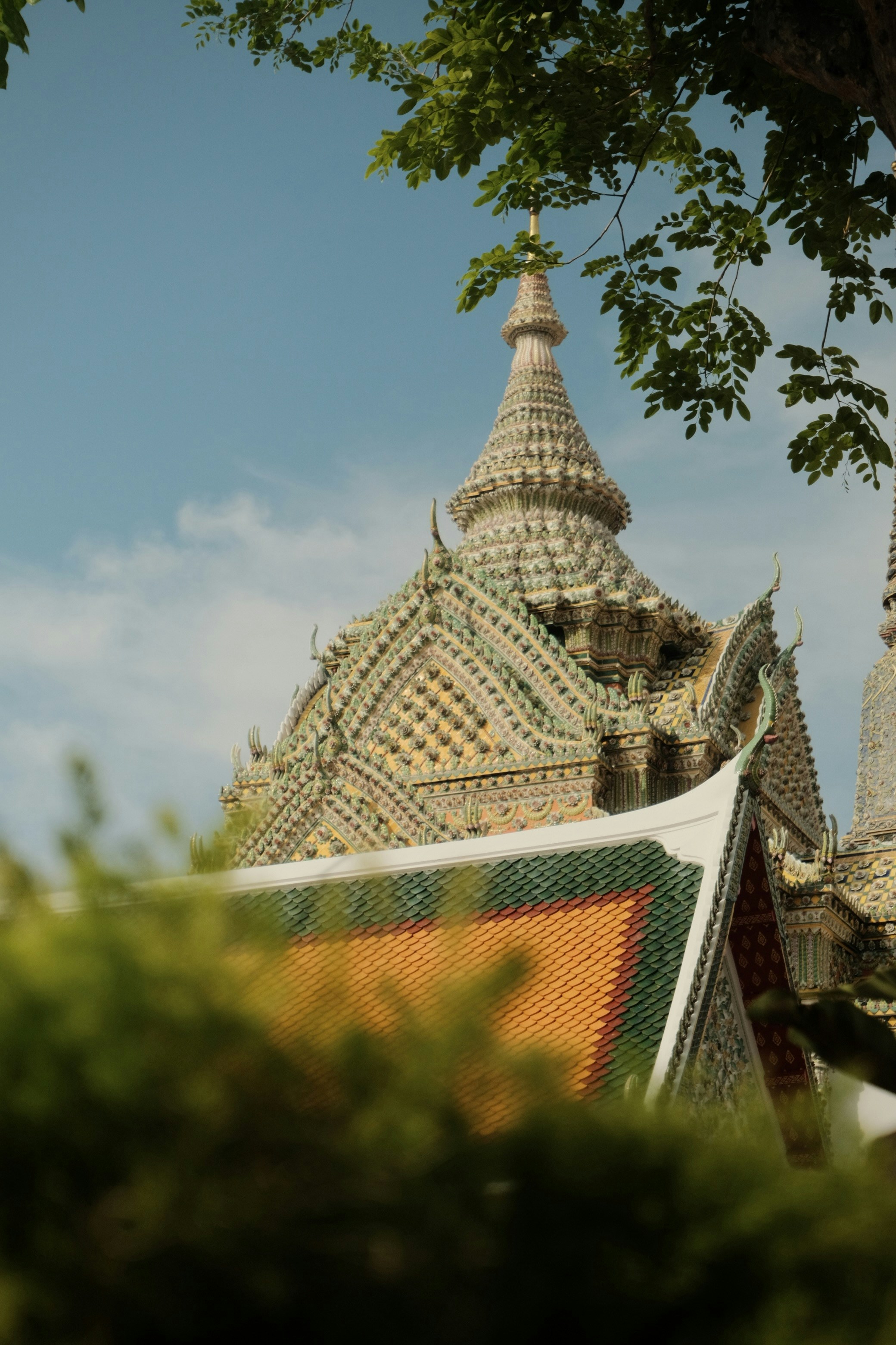 Ornate temple roof with a spire against a blue sky.