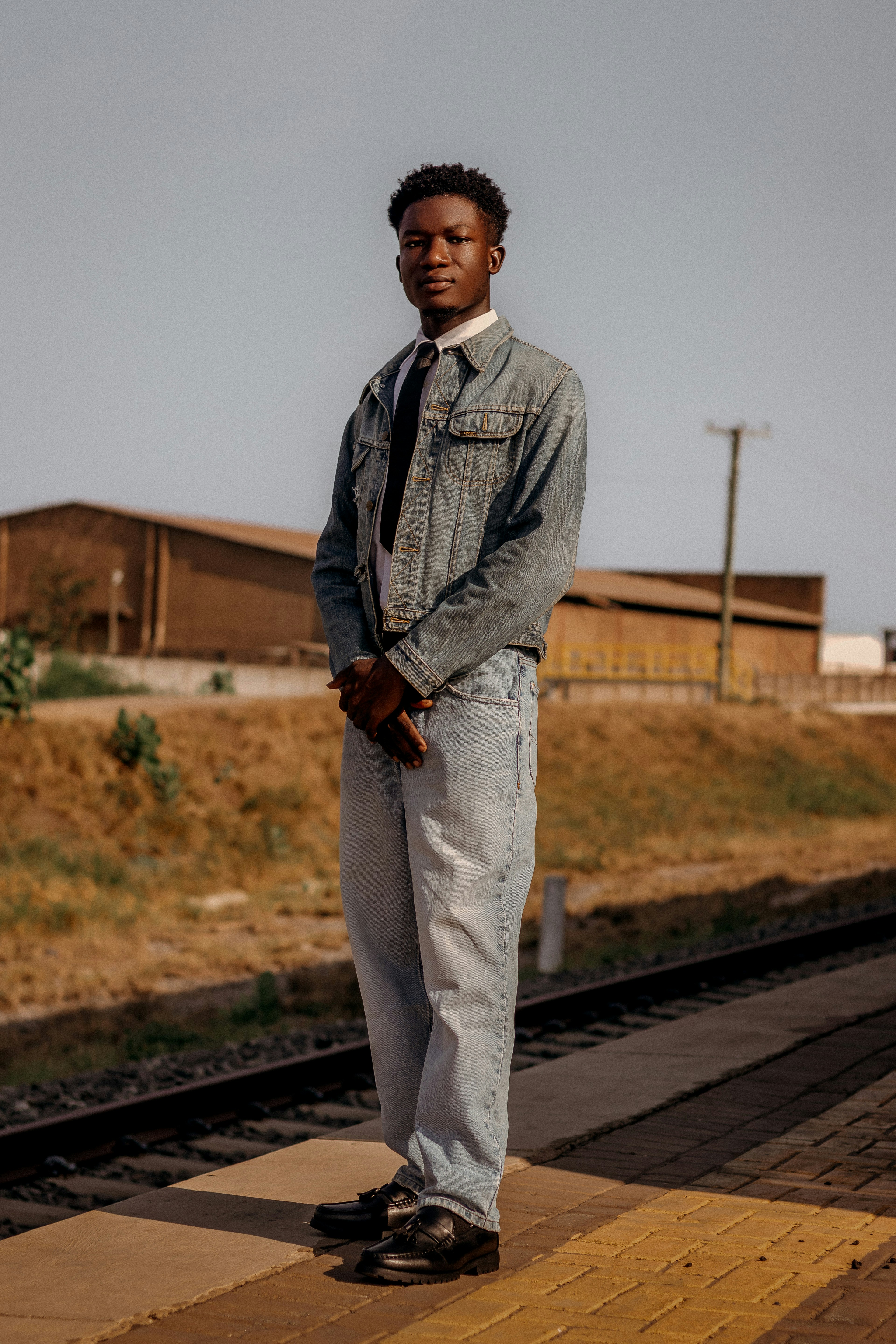 Standing in the Quiet Dawn: A Denim-Clad Portrait by the Tracks