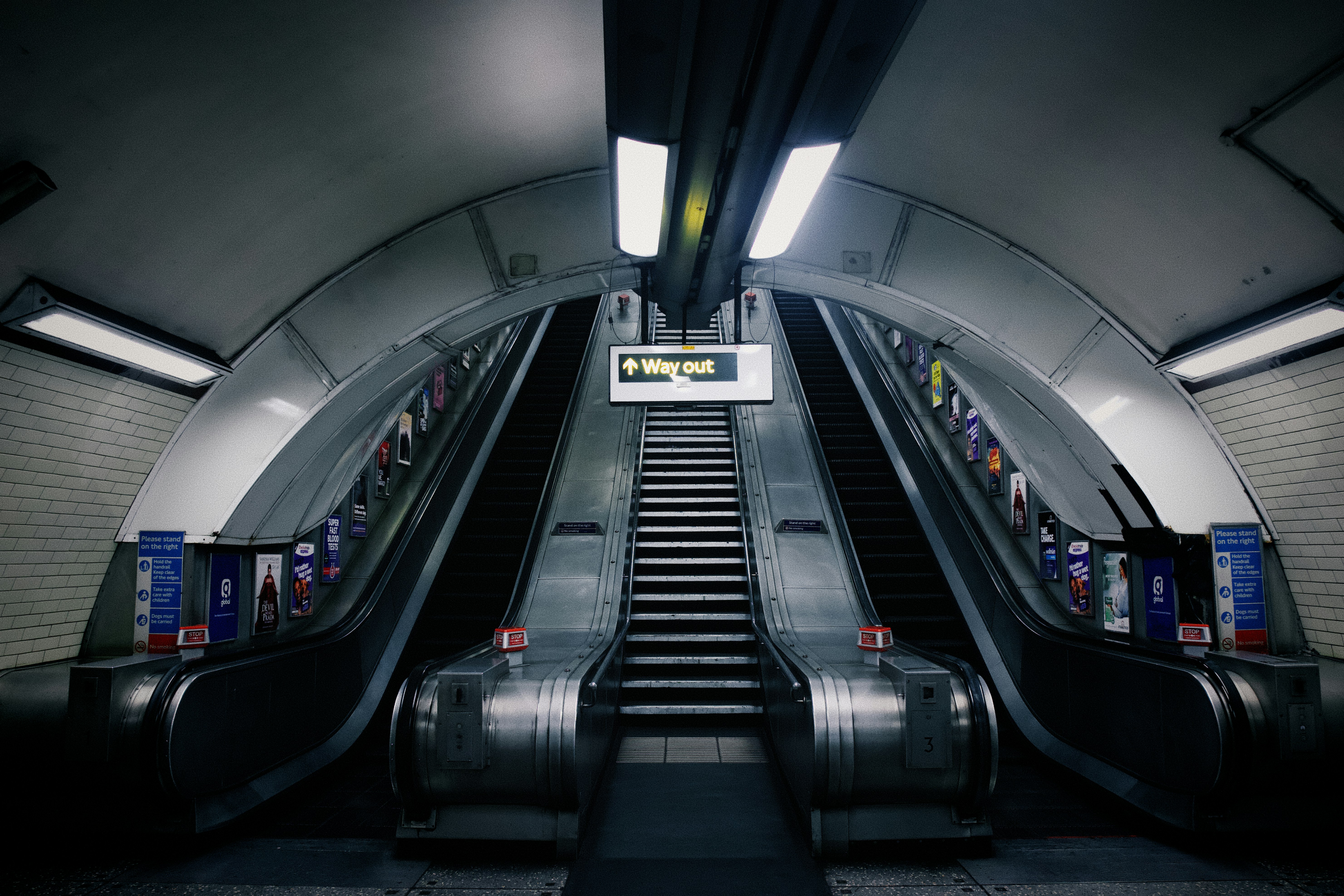 Subway Descent: Centered Escalators Under Neon Arches