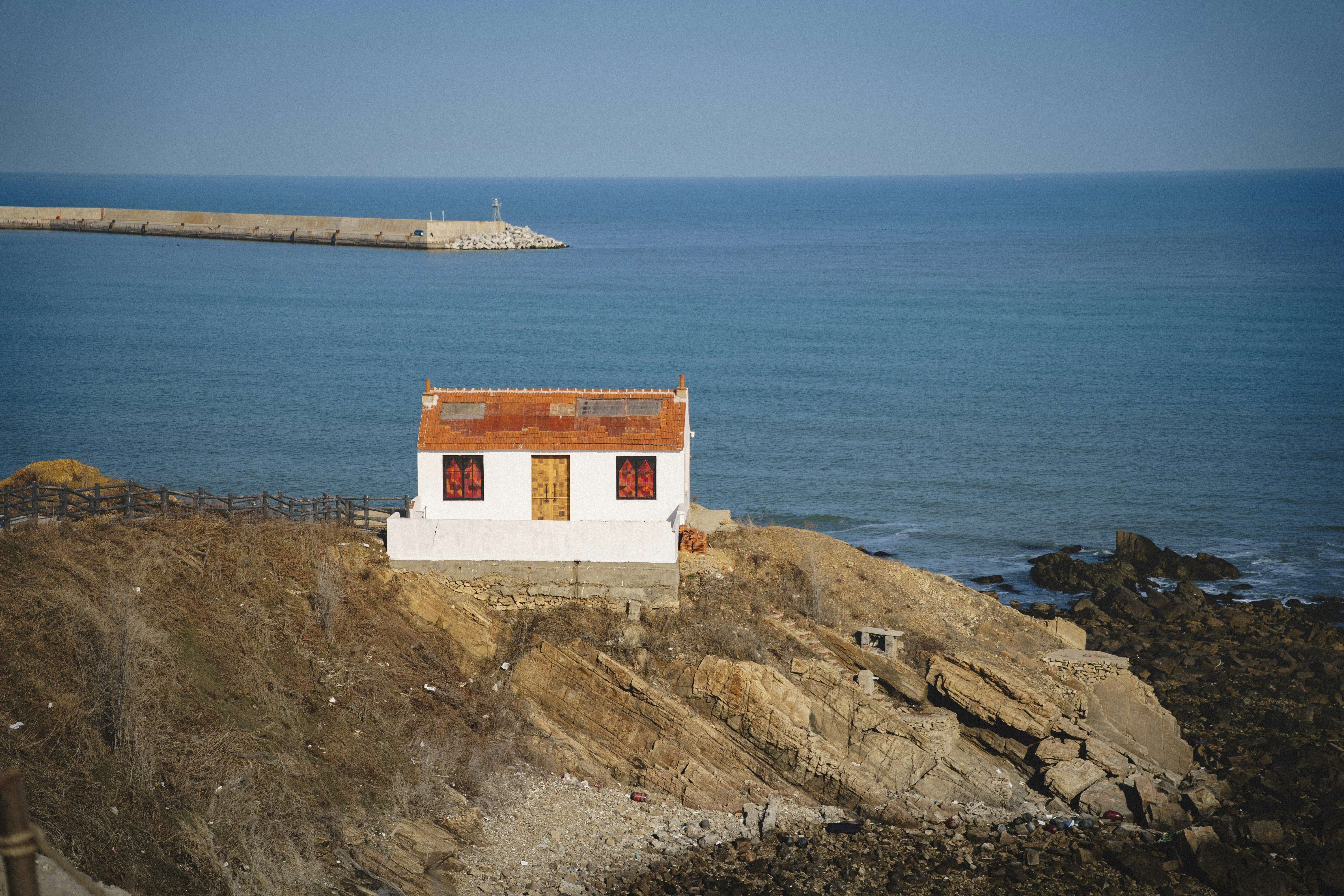 White House on a Rocky Shore Under a Calm Sea