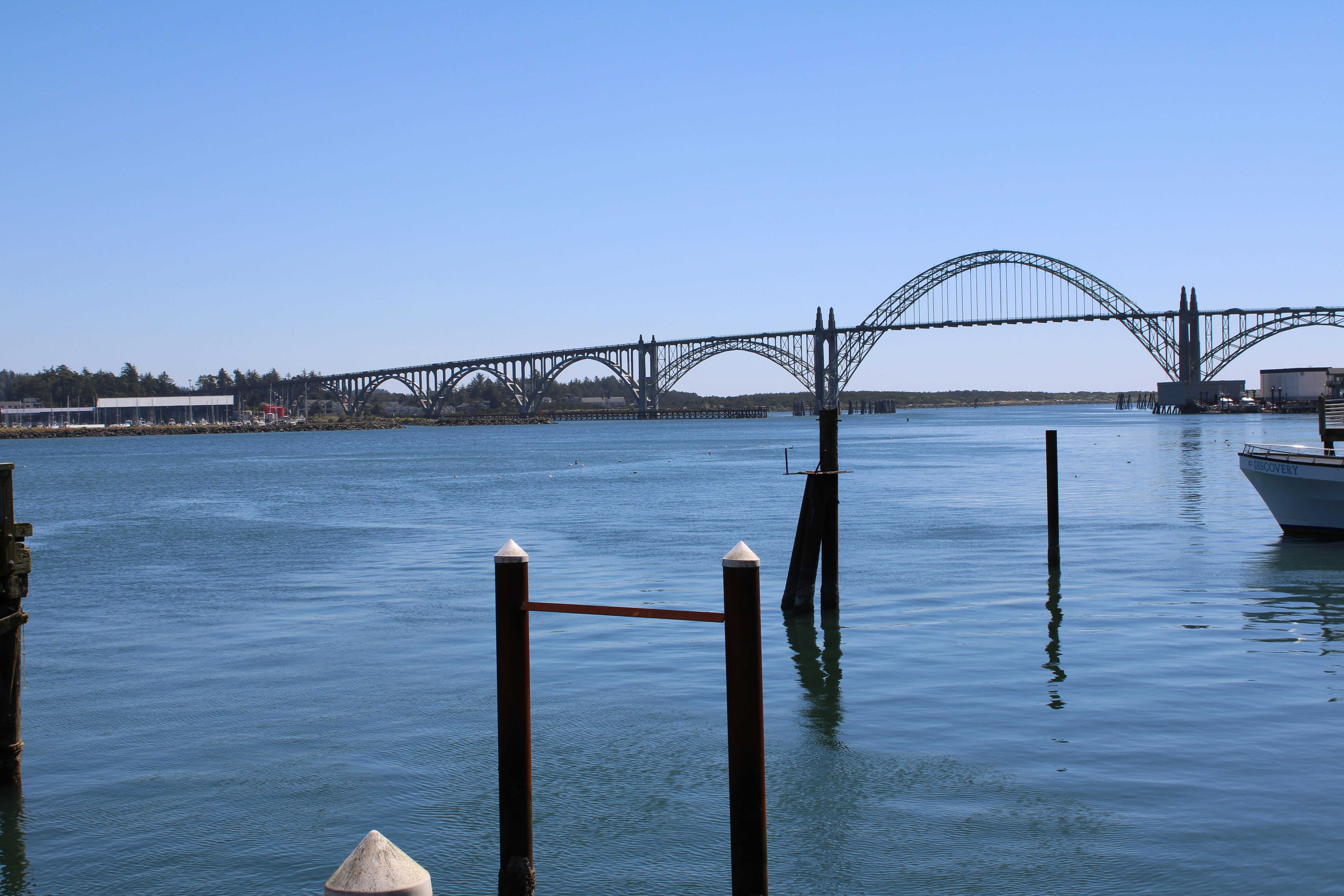 Toward the Blue Span: A Quiet Waterfront with a Distant Arch