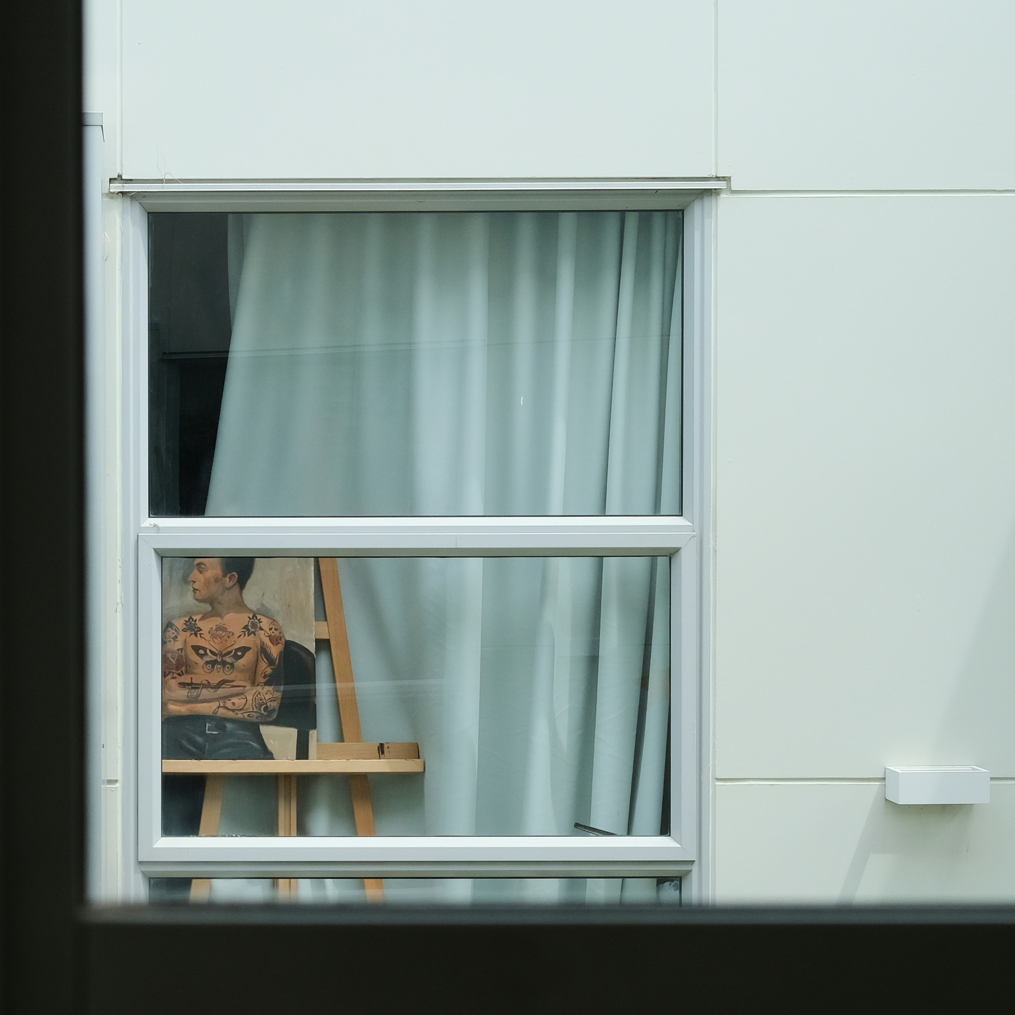 Tattooed Artist in a Window: Quiet Studio Reflected